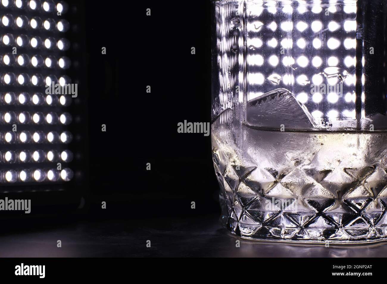 A glass of hard alcohol with ice on a bar counter. Whiskey with soda in ...