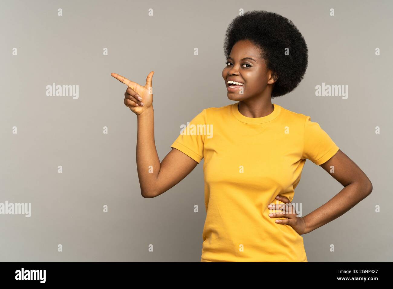 Joyful african american woman point finger with cheerful smile. Young ...