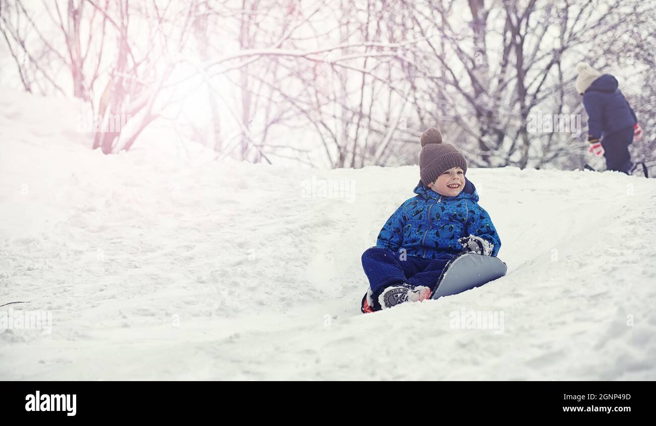 Children in the park in winter. Kids play with snow on playground. They ...