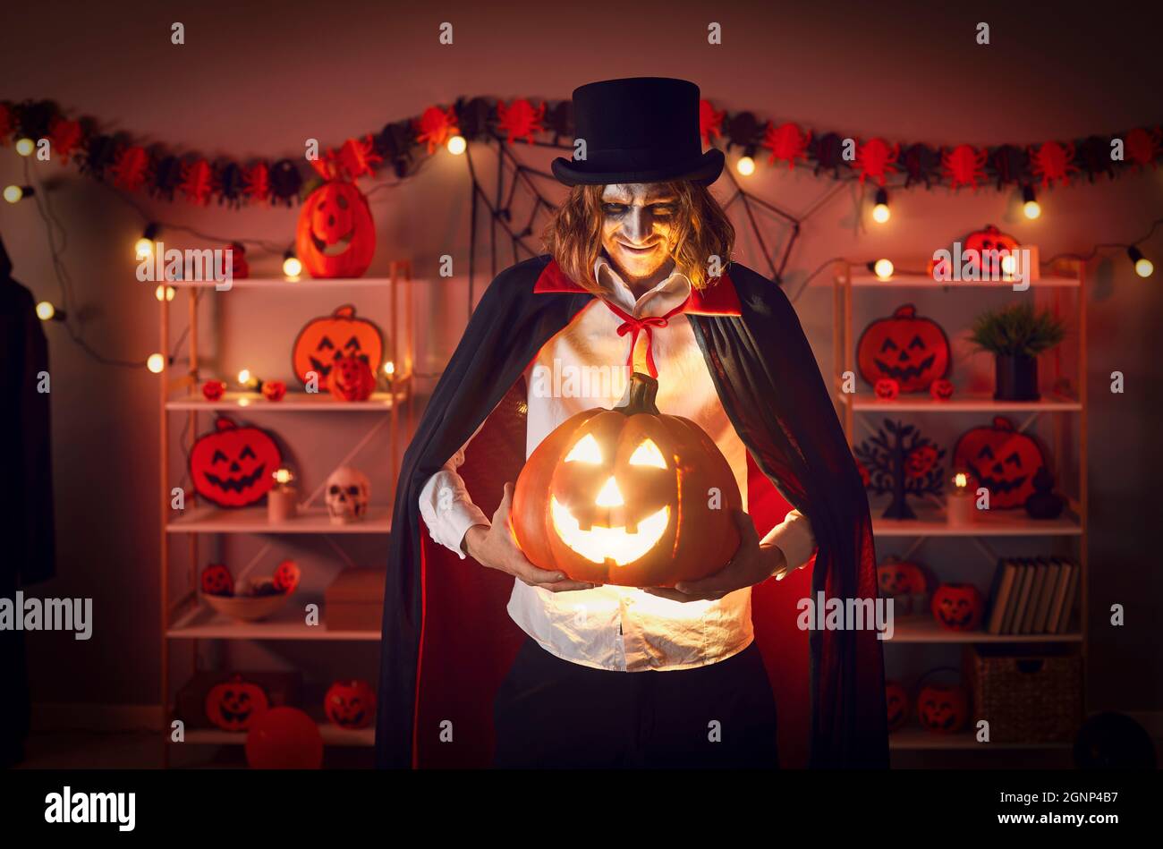 Adult man in a spooky Halloween costume holding his smiling orange jack ...