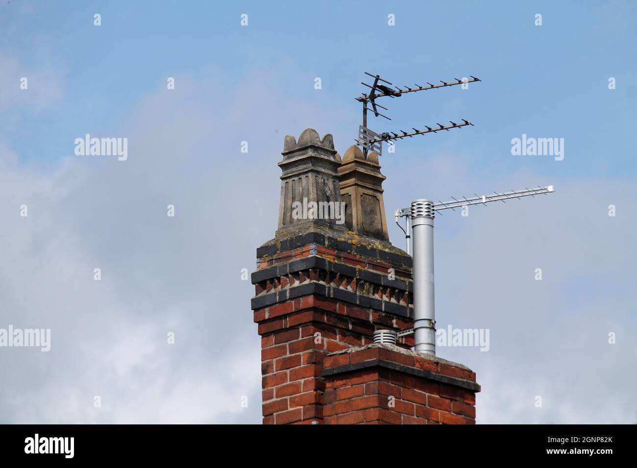A Collection of Flues and Aerials on Two Brick Chimneys Stock Photo - Alamy