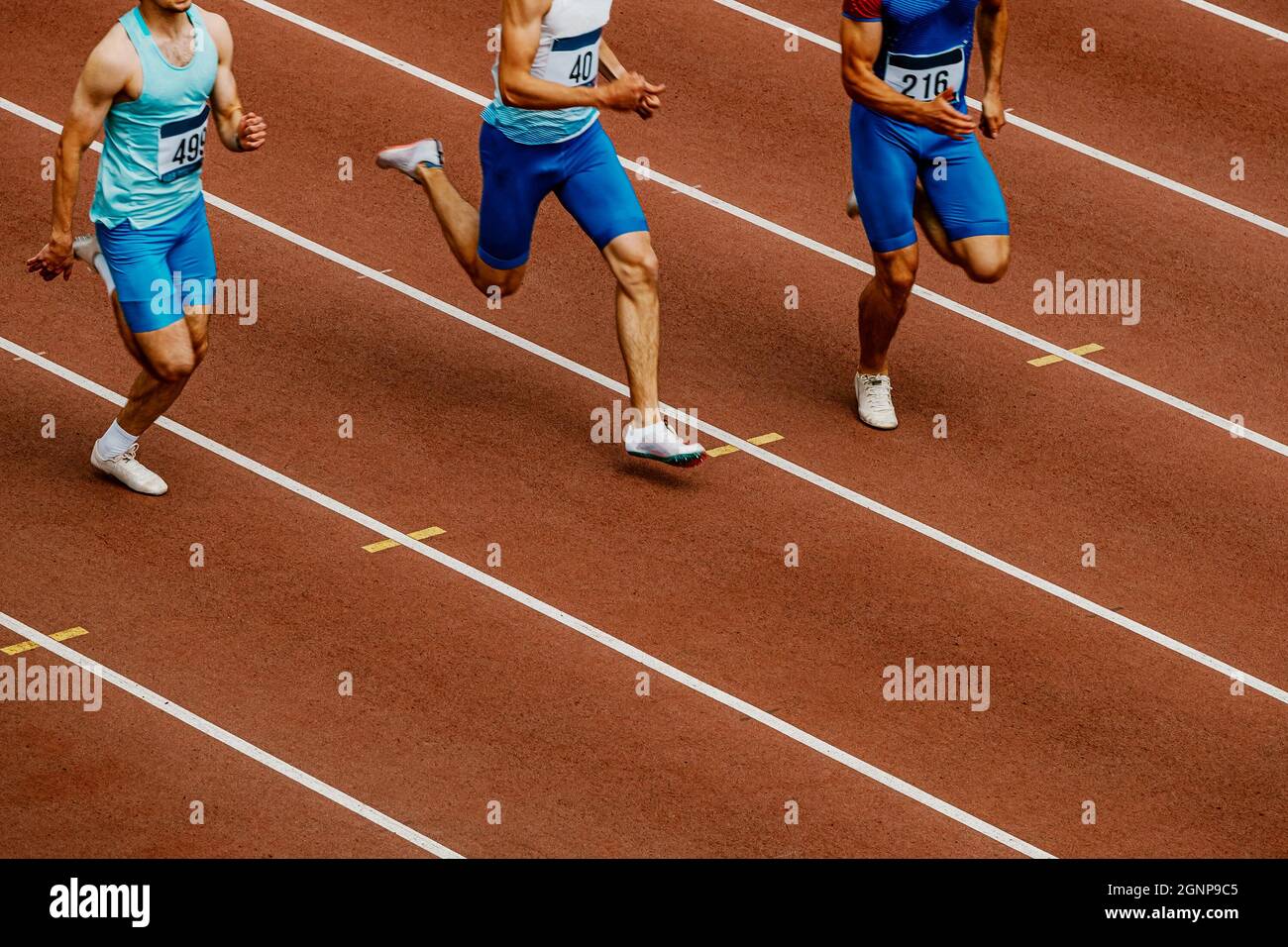group male runners run on track stadium in track and field competition ...