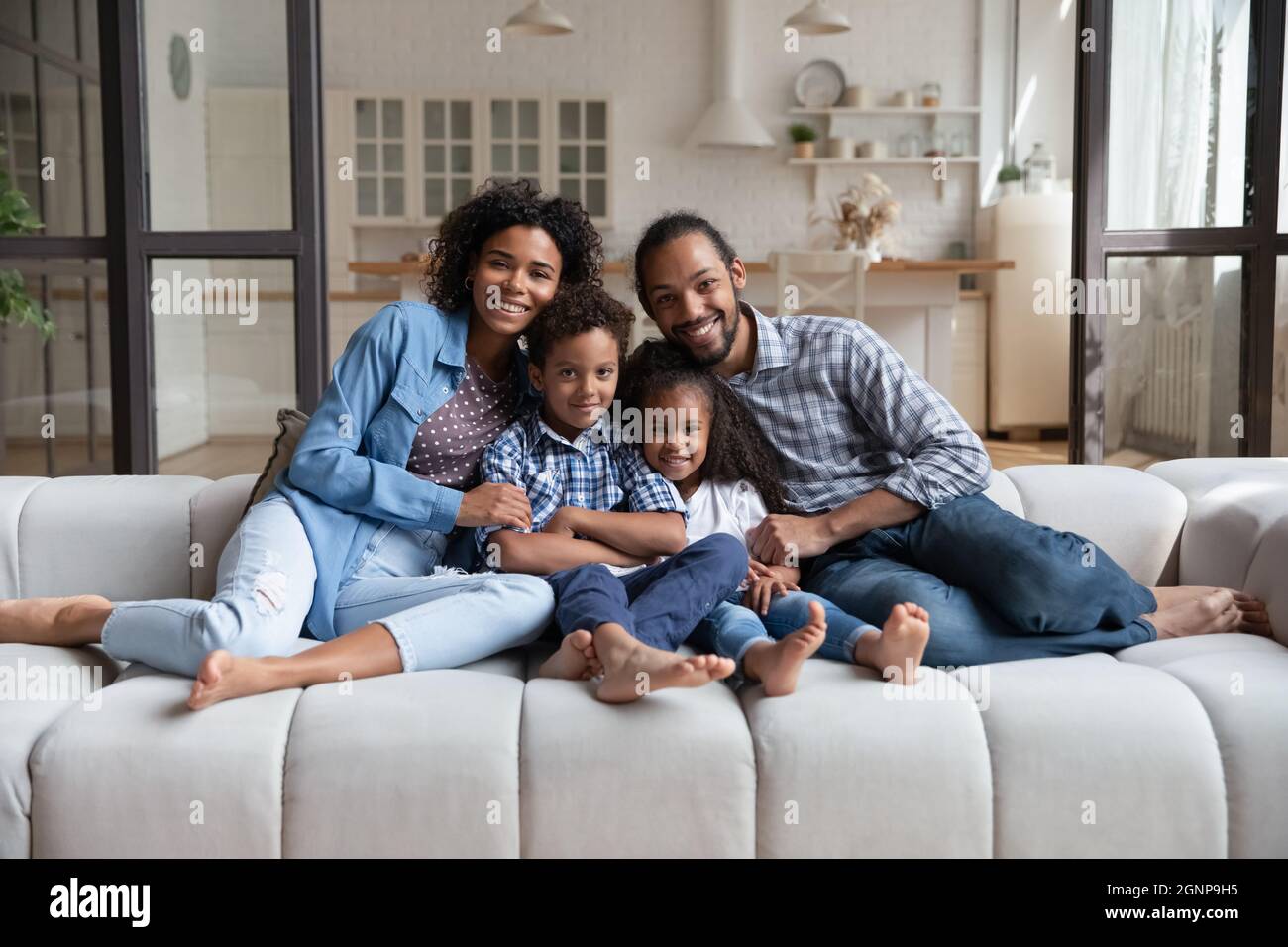 Portrait African American parents with little kids sitting on couch ...