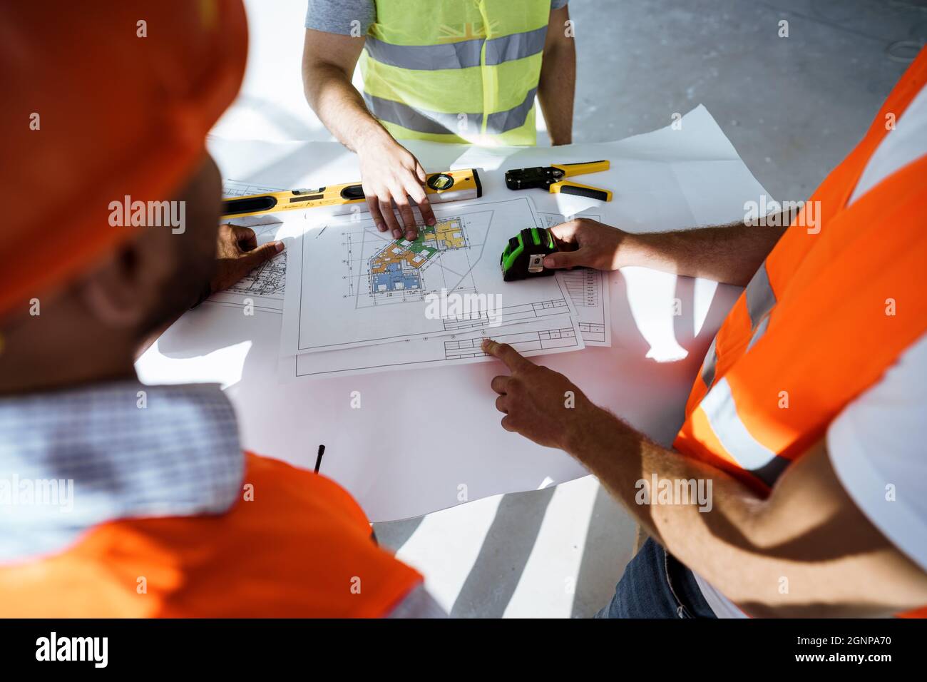 Close up of three man engineers looking at blueprint on construction ...