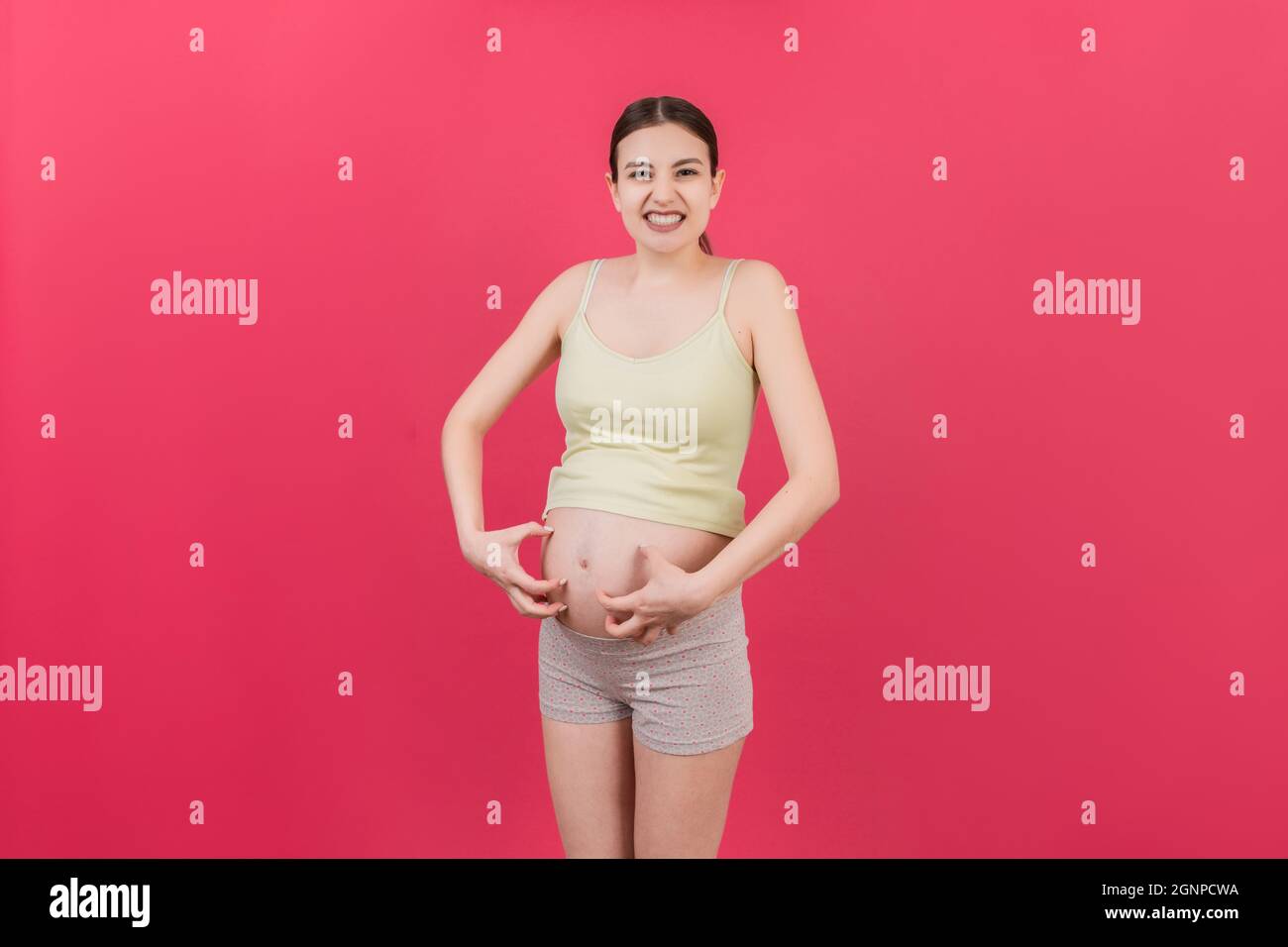 Pregnant woman scratching her belly on colored background Stock Photo ...