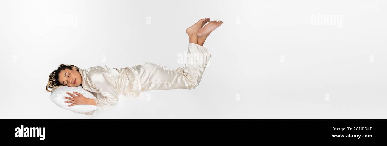 african american woman sleeping on pillow while levitating isolated on ...
