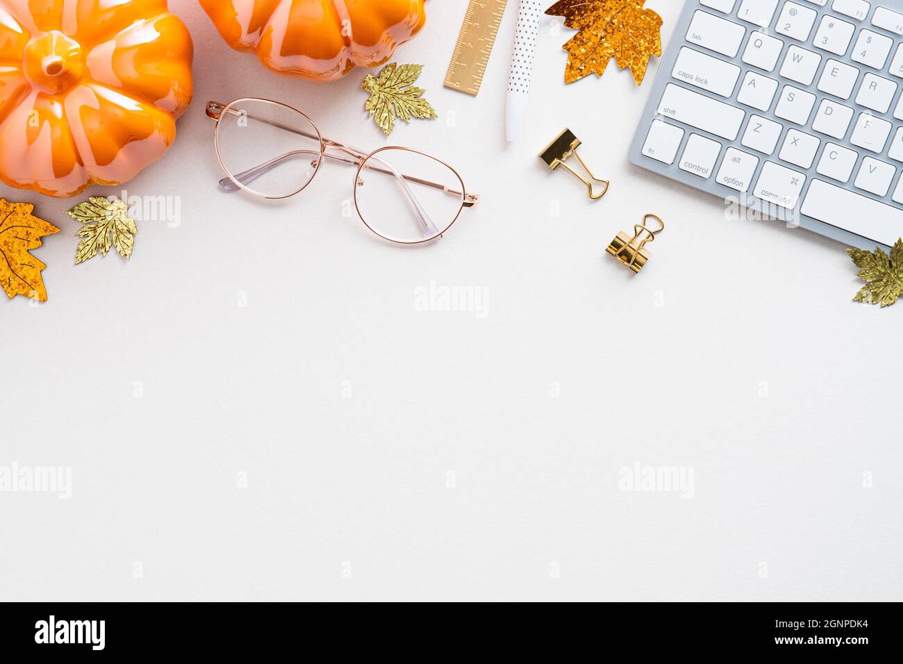 Autumn desk table with pumpkins, keyboard, glasses on white background ...
