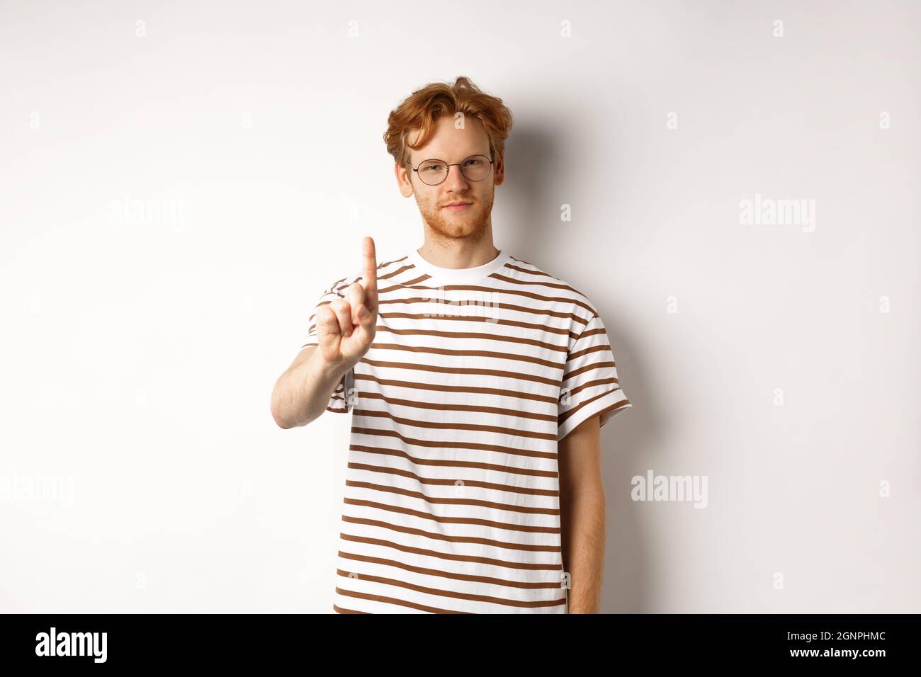 Young man with red hair and glasses shaking finger in prohibition ...