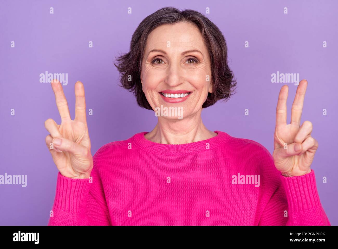 Portrait of attractive cheerful mature woman showing double v-sign good ...