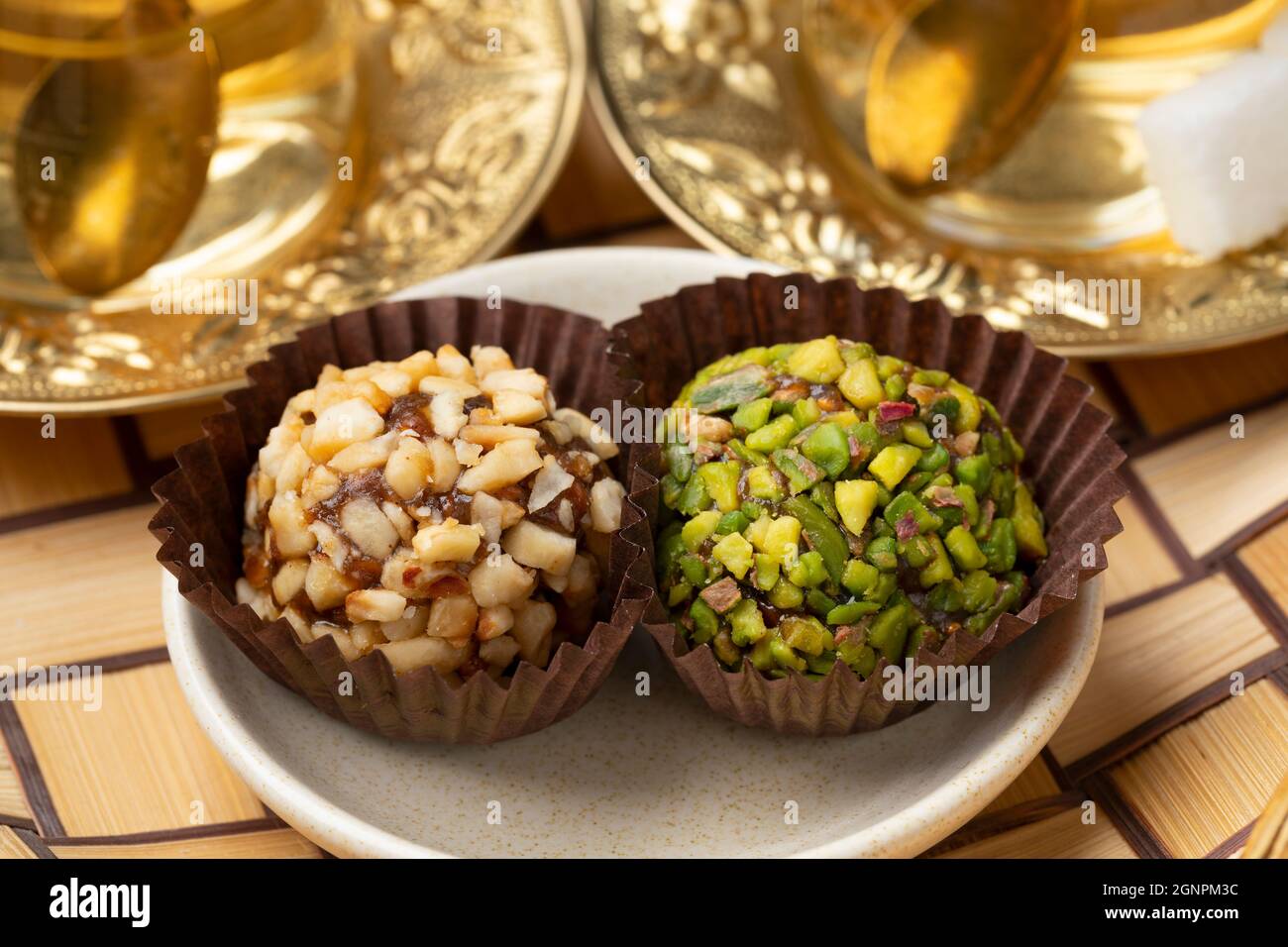 Pair of sweet Turkisch date bonbons decorated with nuts in front of tea ...