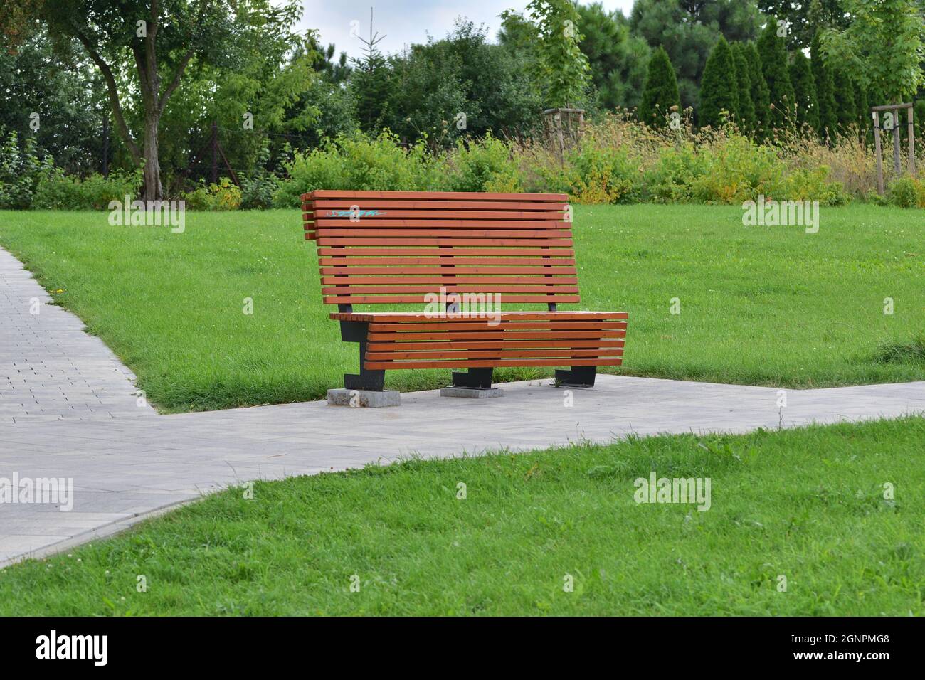 Park bench by a pedestrian path on a cloudy day. Rest Stock Photo - Alamy