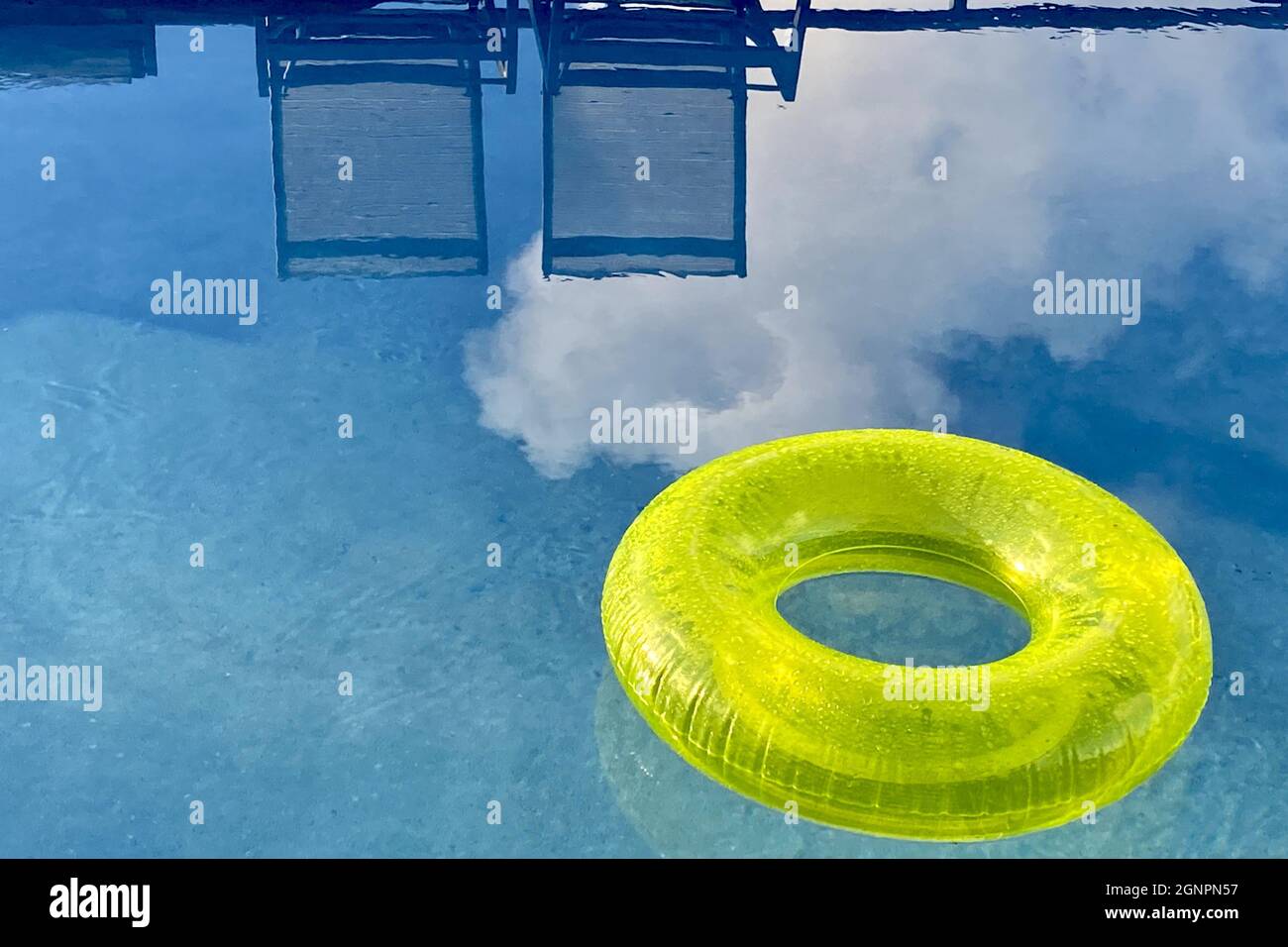 Yellow inflatable pool toy floating on the water surface reflecting two ...