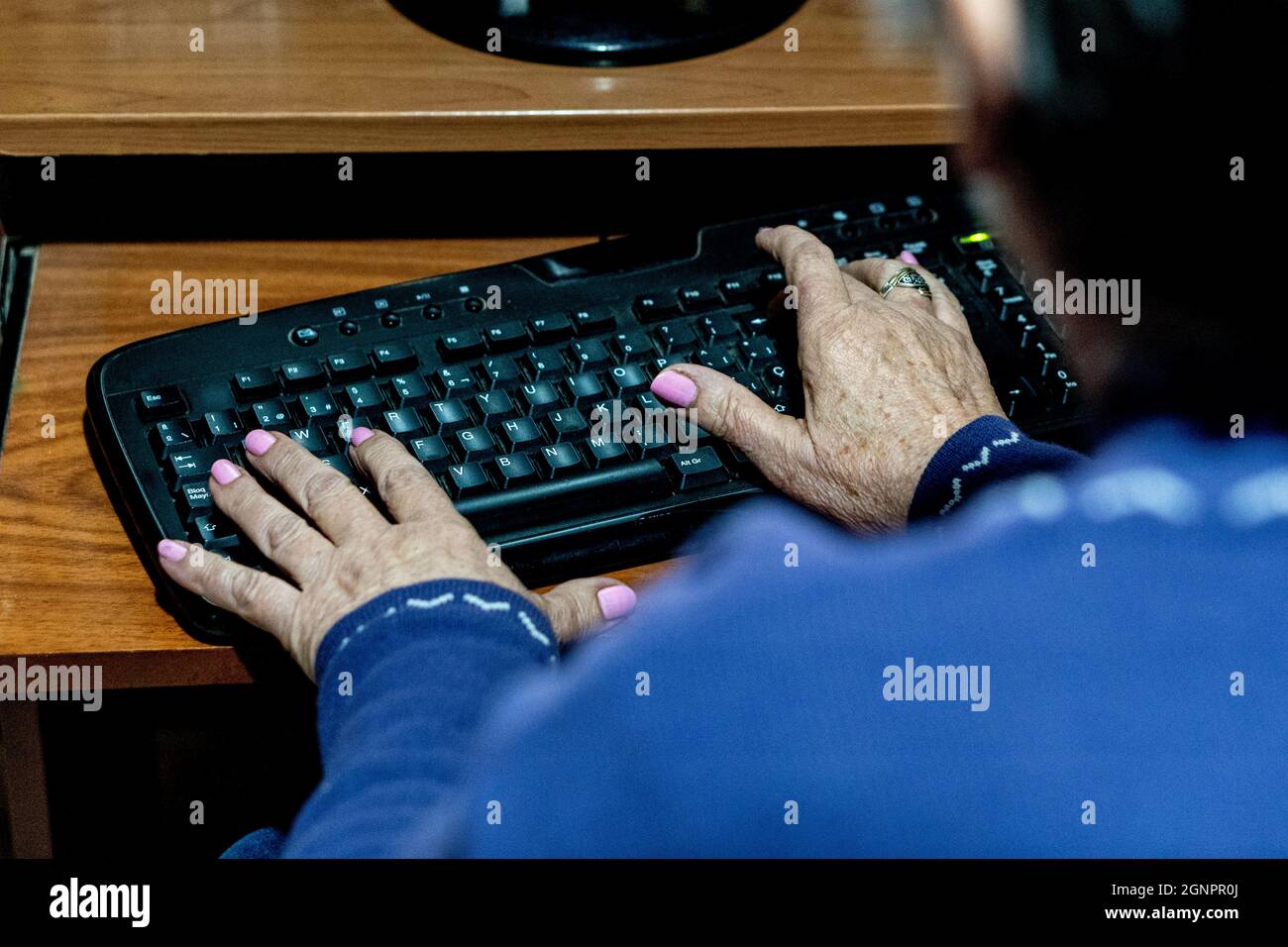 Over-the-shoulder view of a senior female typing on a keyboard Stock ...