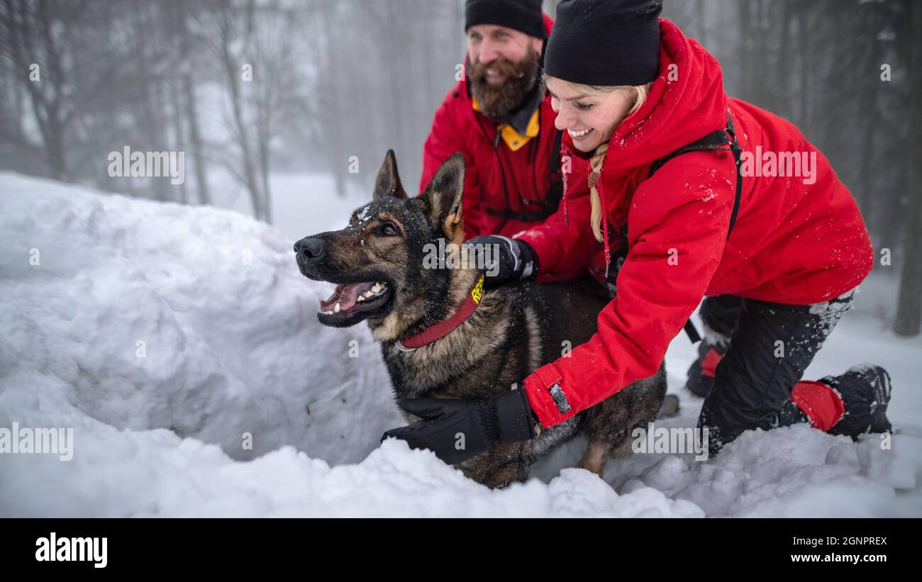 Happy mountain rescue service with dog on operation outdoors in winter ...