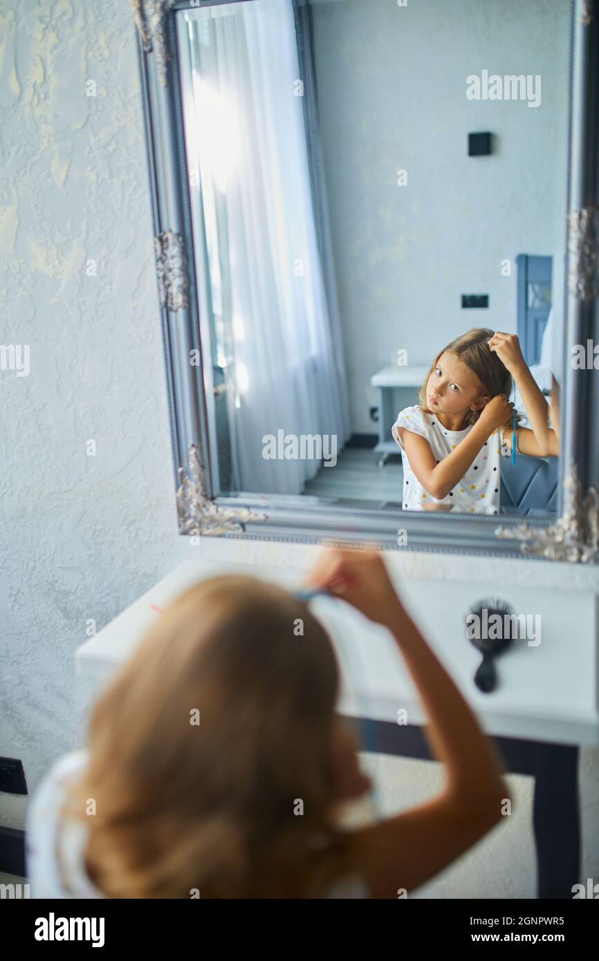 Pretty Little girl combing by herself hair in front of a mirror Stock ...