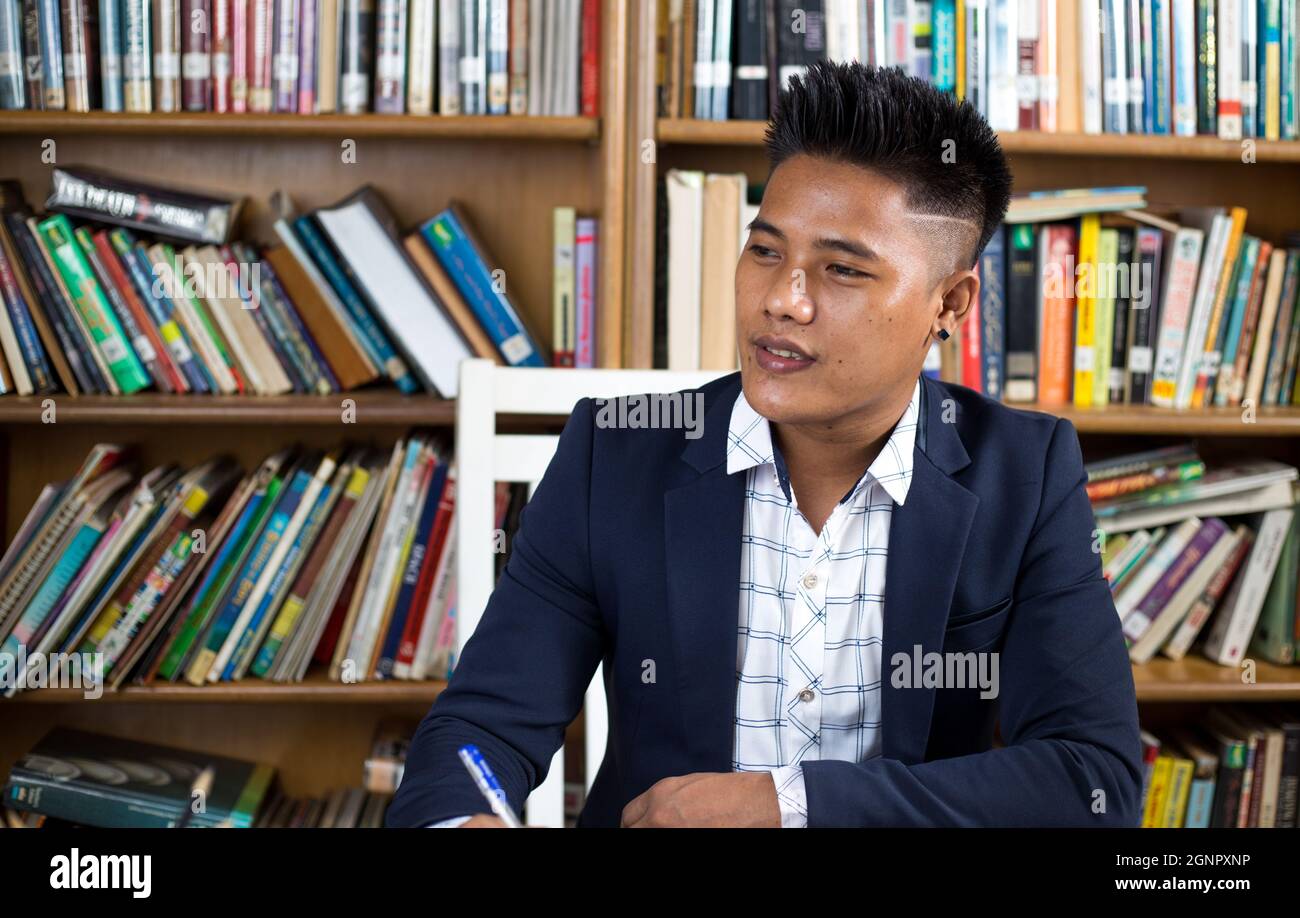 Southeast Asian guy from Malaysia studying in a library wearing a shirt ...