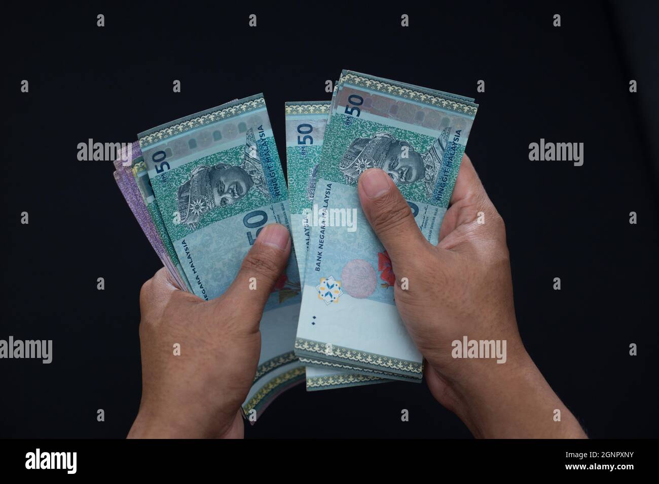 Male's hands holding Malaysian ringgit banknotes isolated on a black ...