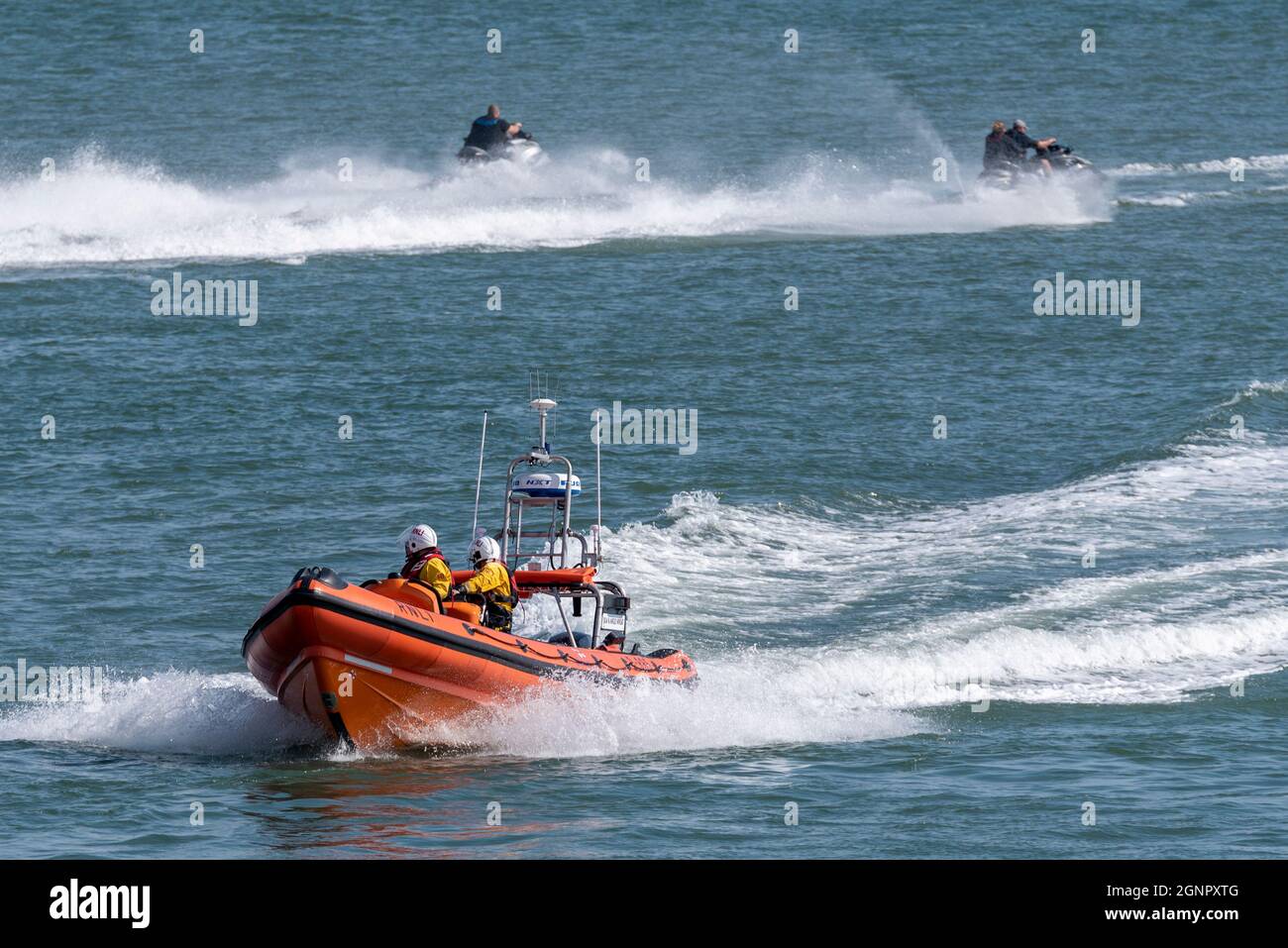 RNLI lifeboat and crew in rib boat approaching pier lifeboat station in ...