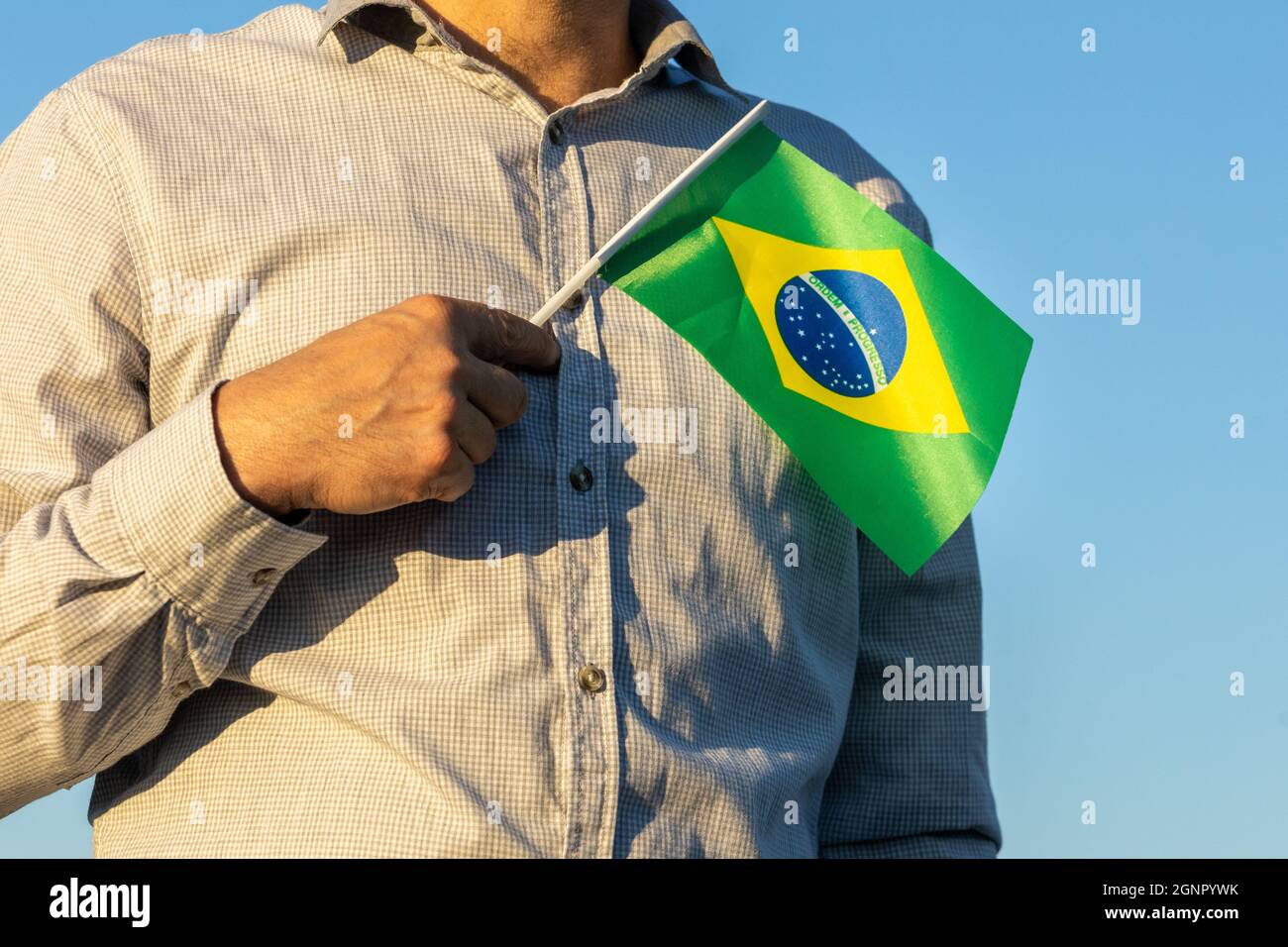 Man holding a brazil flag to his heart with pride Stock Photo - Alamy