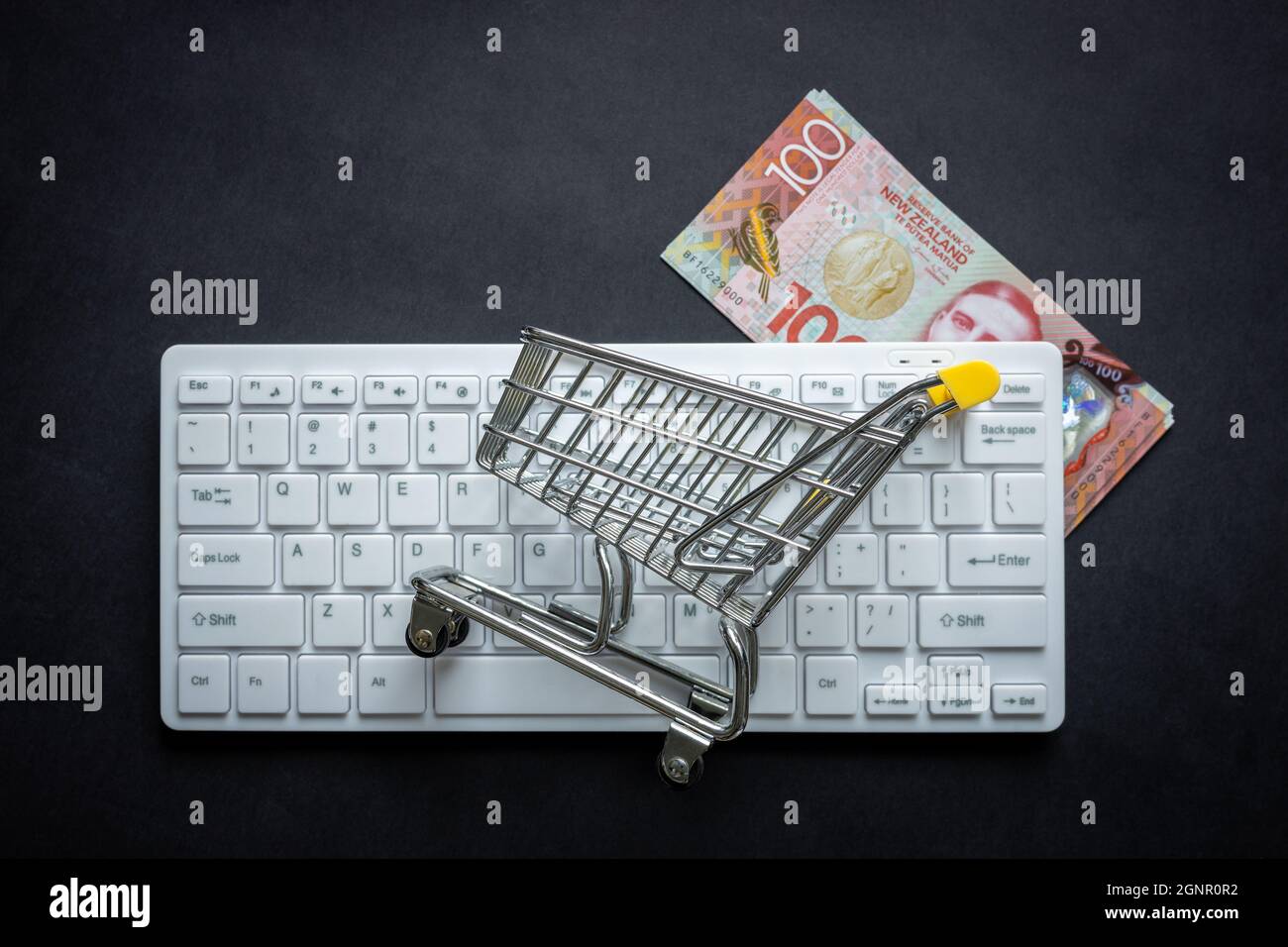 New Zealand dollar, White computer keyboard, Miniature shopping cart ...
