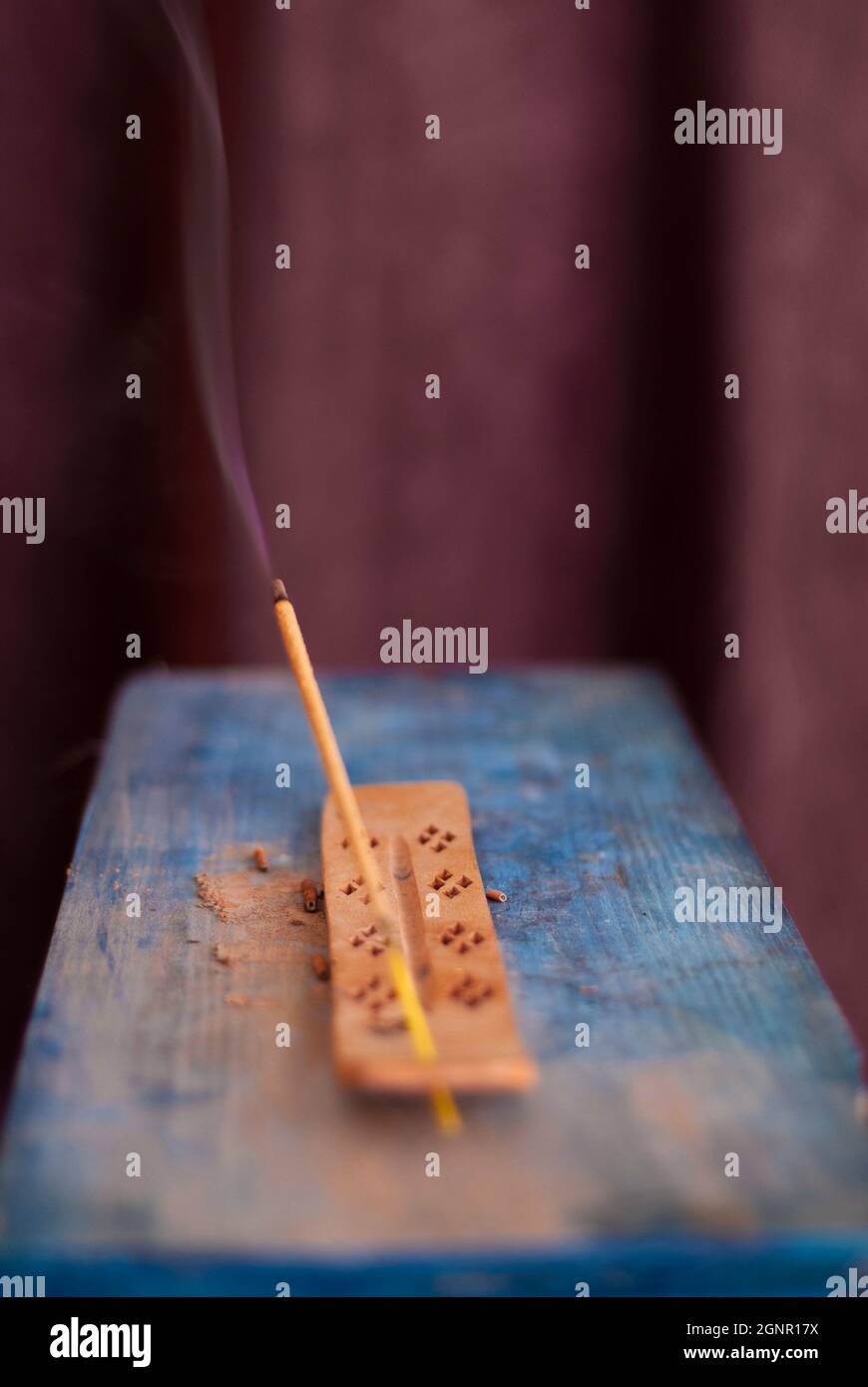 incense stick lit with smoke thread with dark background on sky blue ...