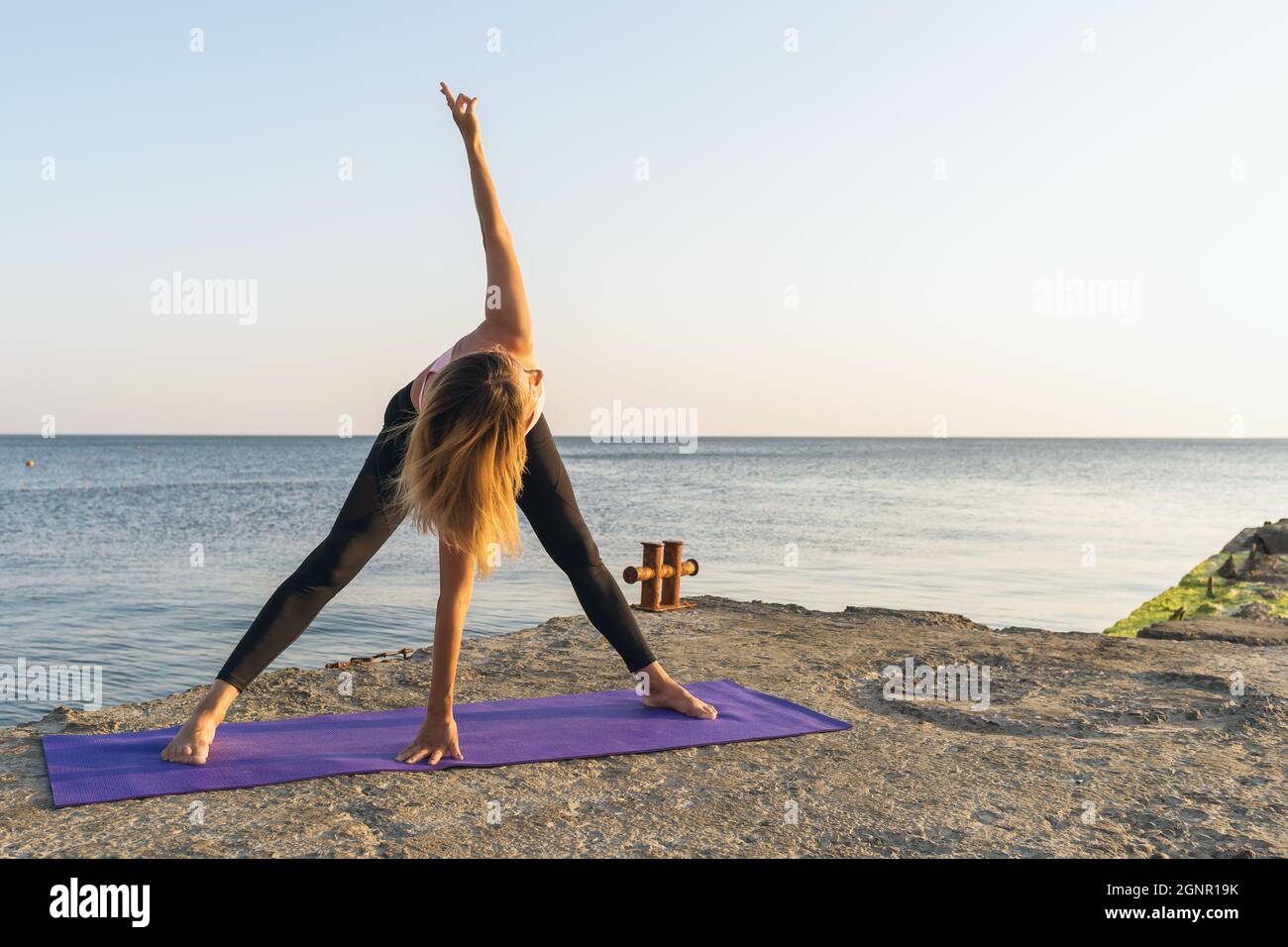 A woman practicing yoga doing the Parivritta Padottanasana twisting ...