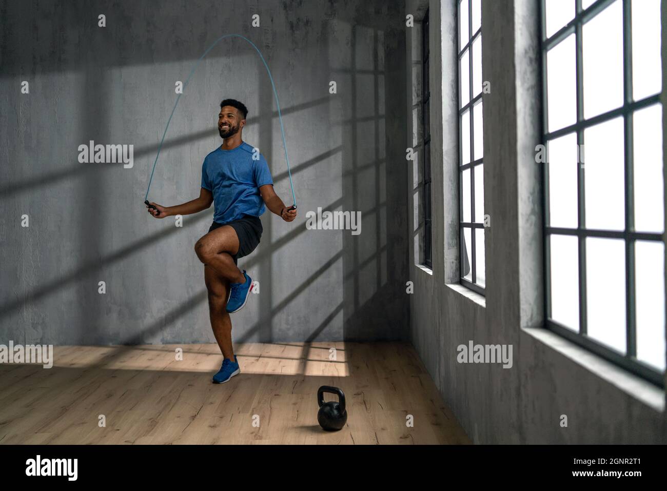 Young African American sportsman using jumping rope indoors, workout ...