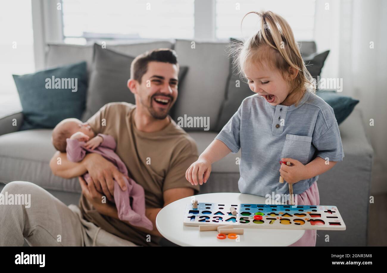 Happy young man taking care of his newborn baby and little daughter ...