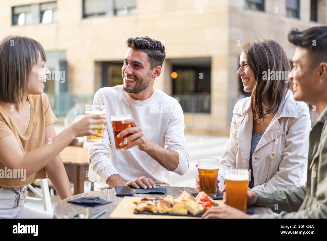 Happy friends drinking beer at the outdoor pub in the city - Friendship ...