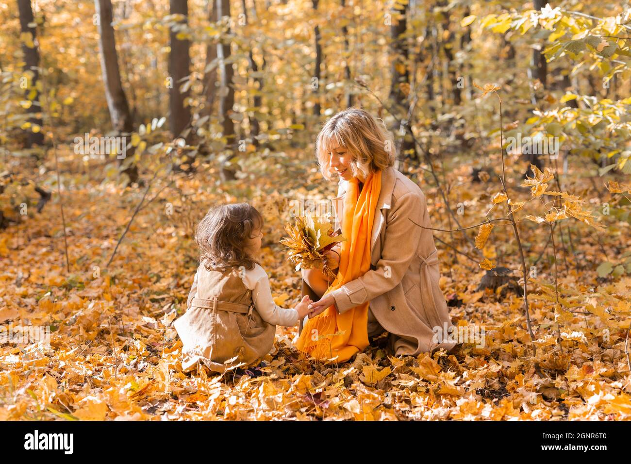 Young mother with her little daughter in an autumn park. Fall season ...