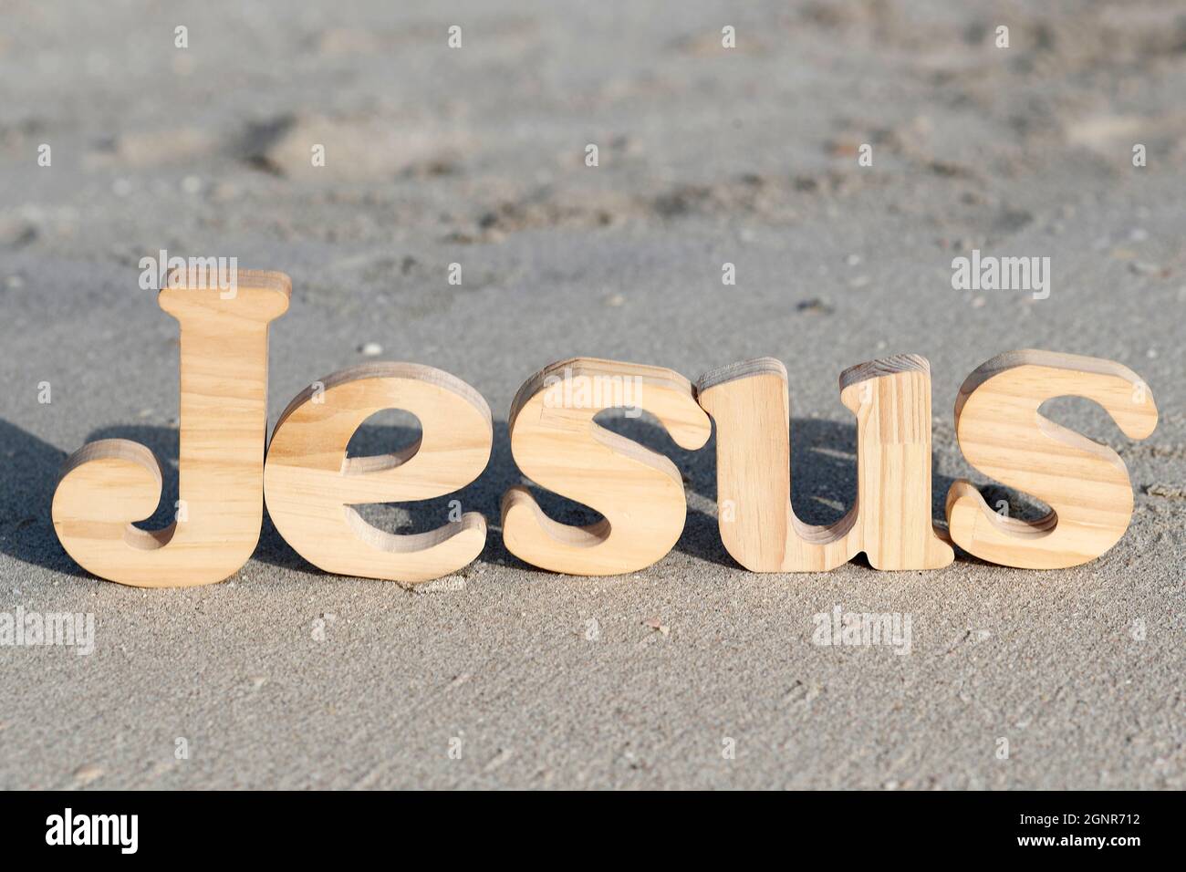 Wooden letters forming the word Jesus on a background of beach sand ...