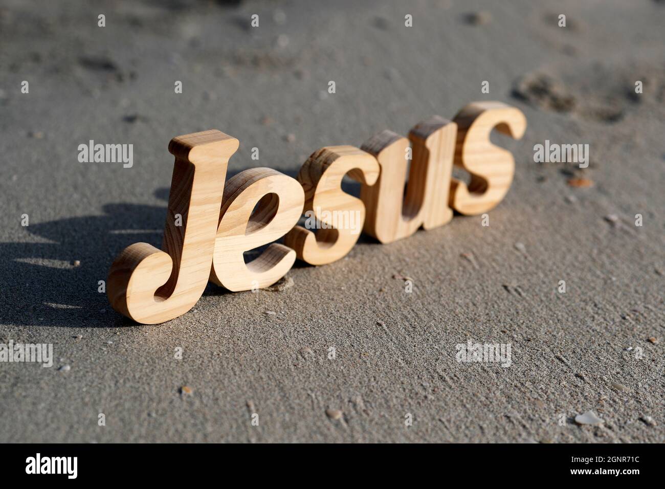 Wooden letters forming the word Jesus on a background of beach sand ...