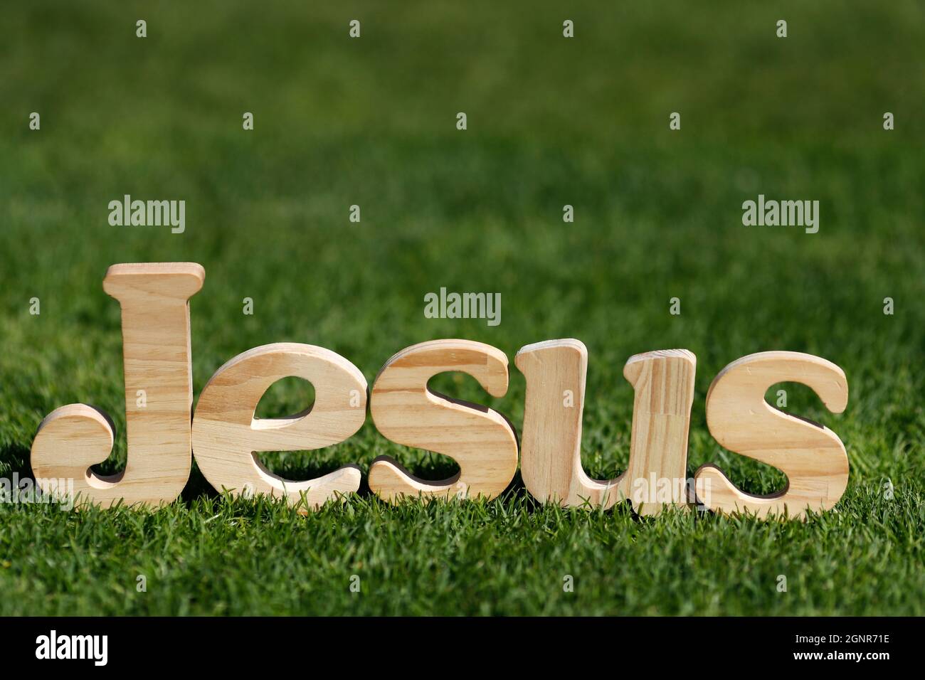 Wooden letters forming the word Jesus on a background of green grass ...