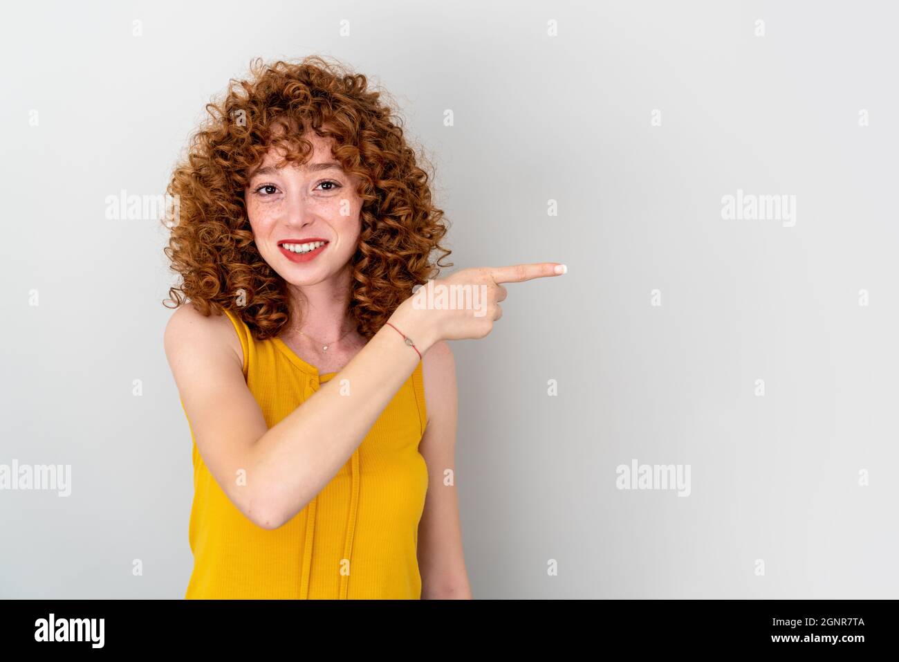 Young red haired woman is pointing a direction. A gesture for using as ...
