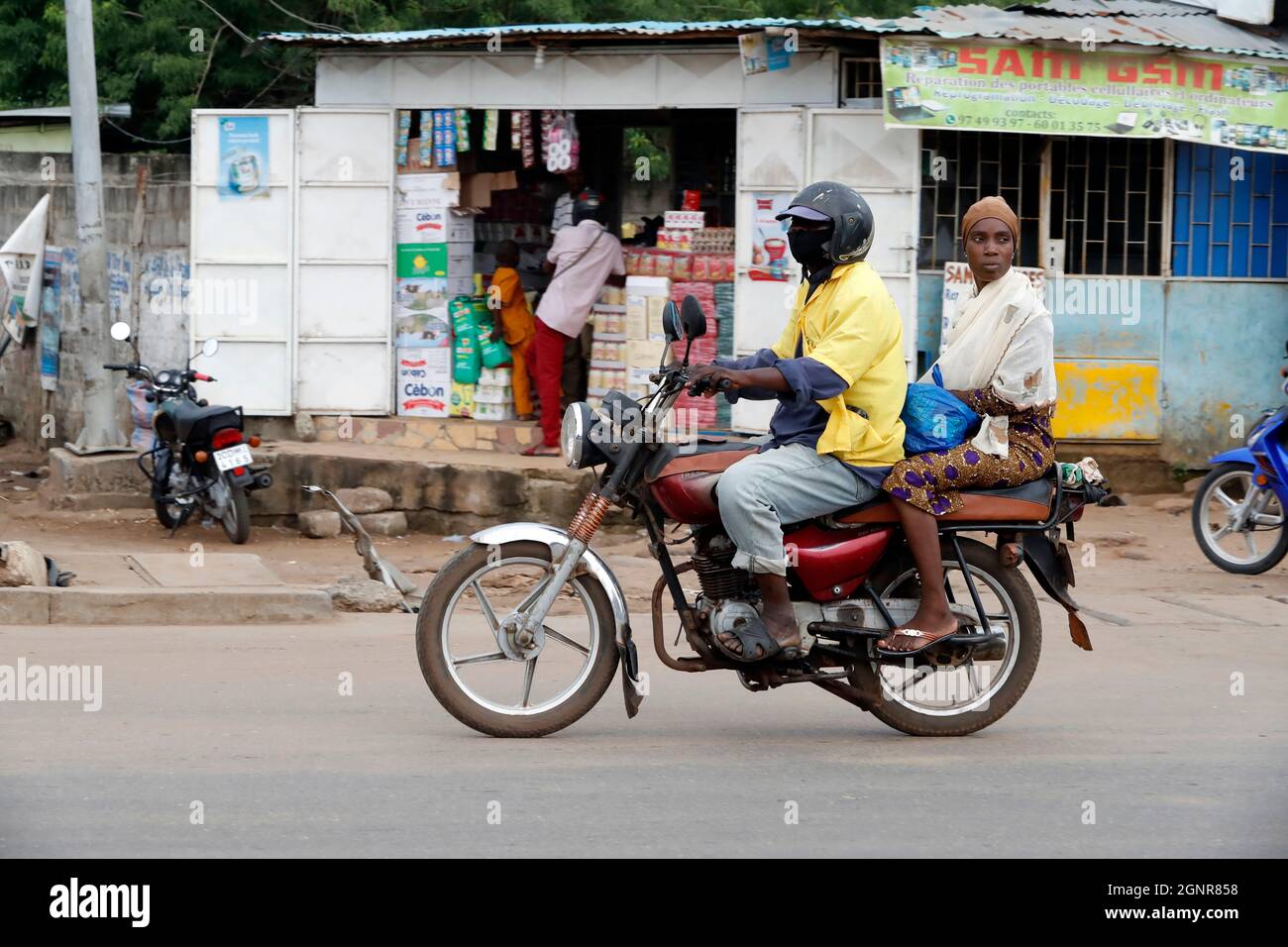 Street scene with african people riding a motorcycle. Benin Stock Photo ...