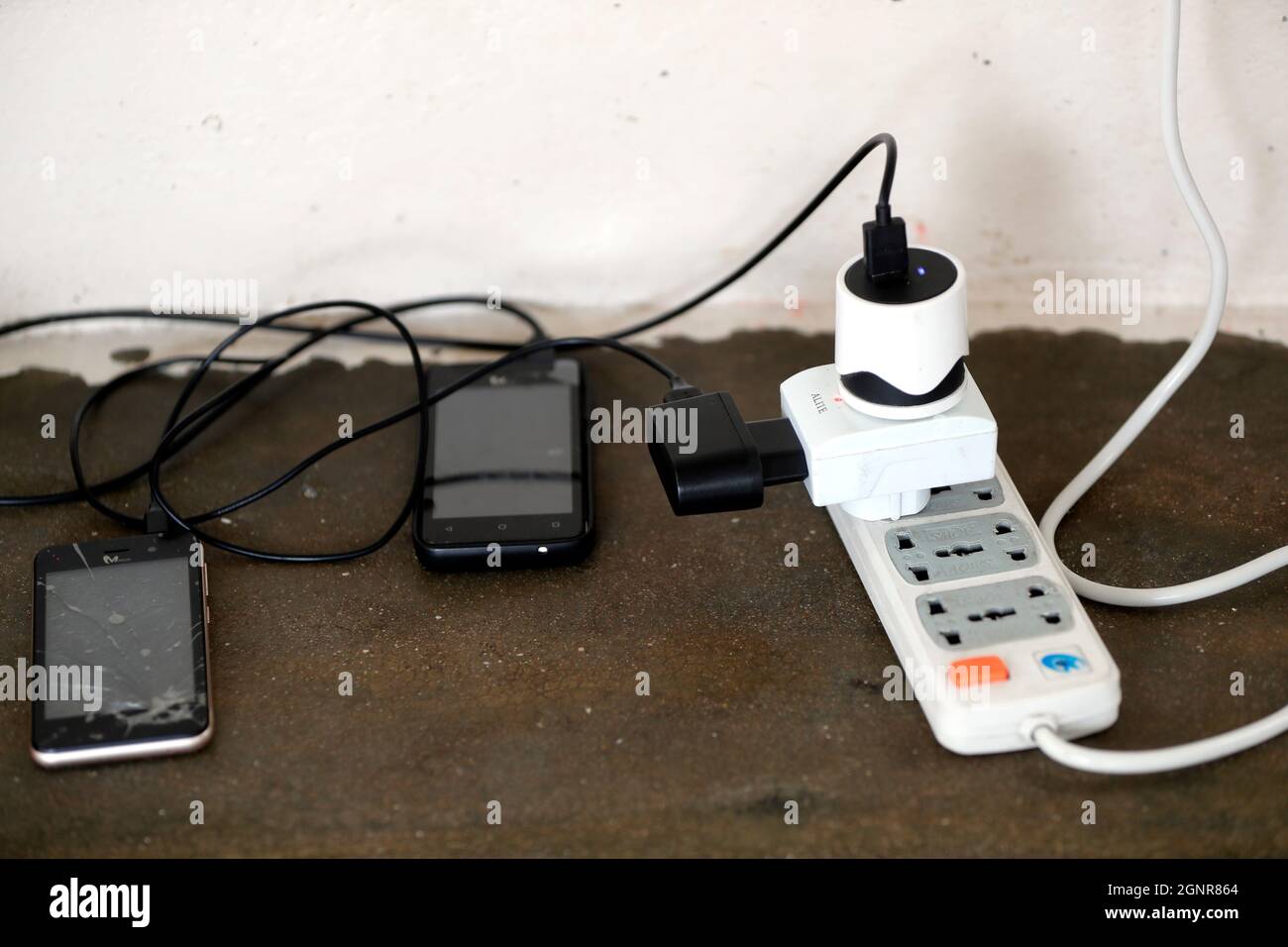 Mobile phones charging on a plug. Benin Stock Photo - Alamy