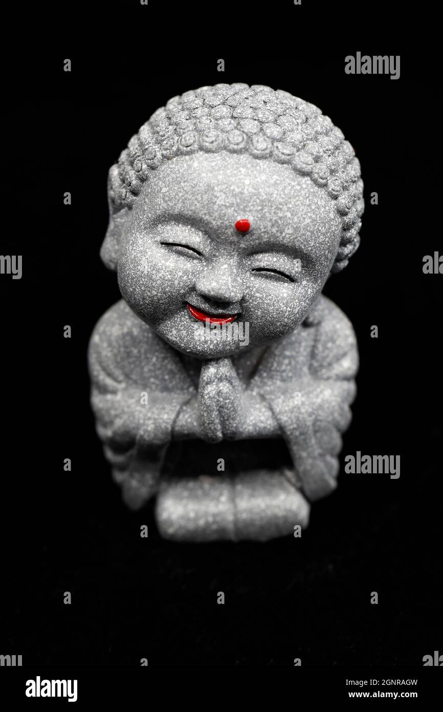 Little Buddhist monk stone statue praying and smiling with eyes closed ...