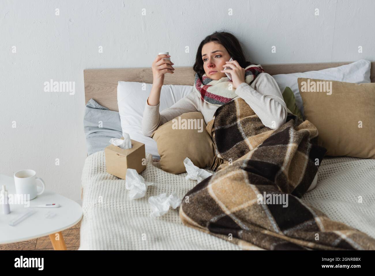 sick woman with pills container talking on mobile phone while lying ...