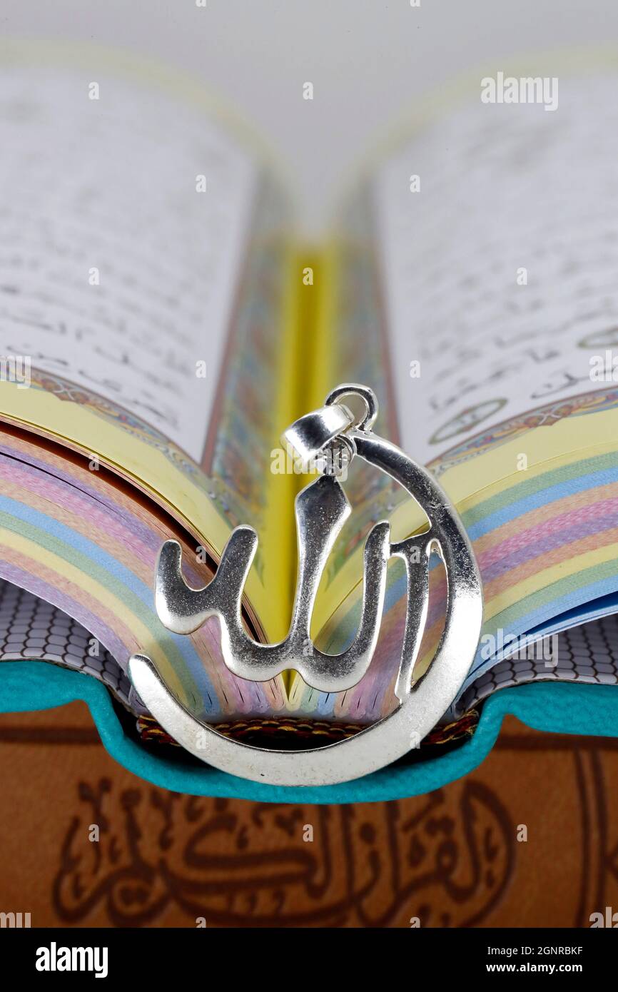 Open Holy Quran with Allah monogram pendant. Religious text. Faith and ...