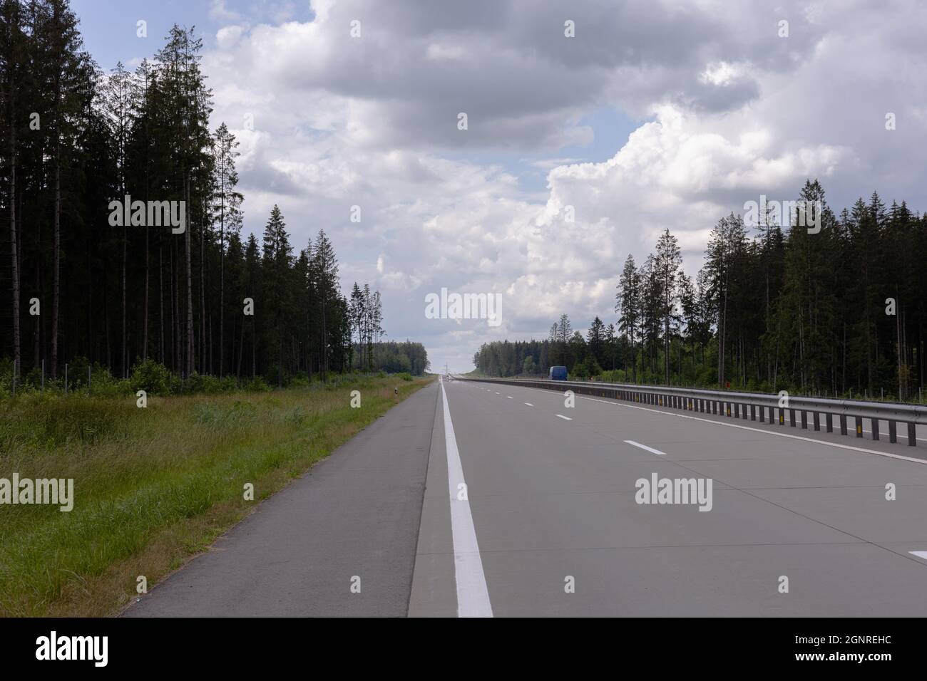 highway road in the countryside, roadside and asphalt, green forest and blue sky on a sunny day ...