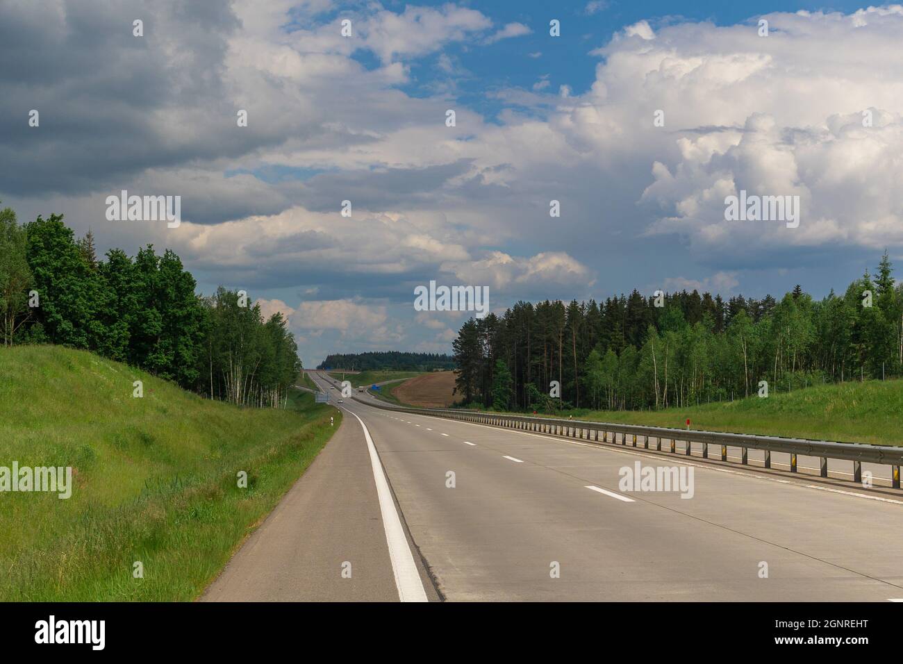 highway road in the countryside, roadside and asphalt, green forest and blue sky on a sunny day ...
