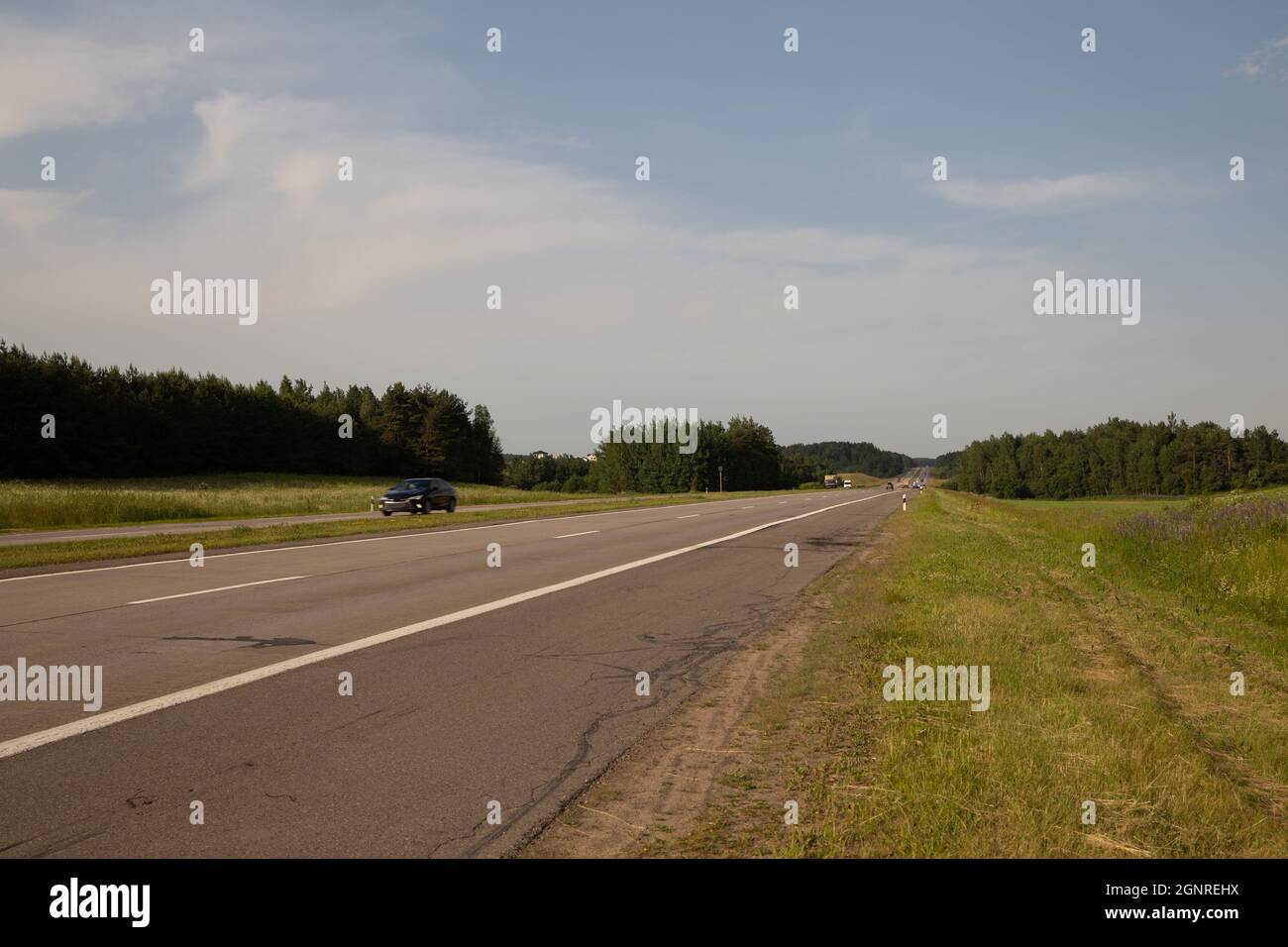 highway road in the countryside, roadside and asphalt, green forest and blue sky on a sunny day ...