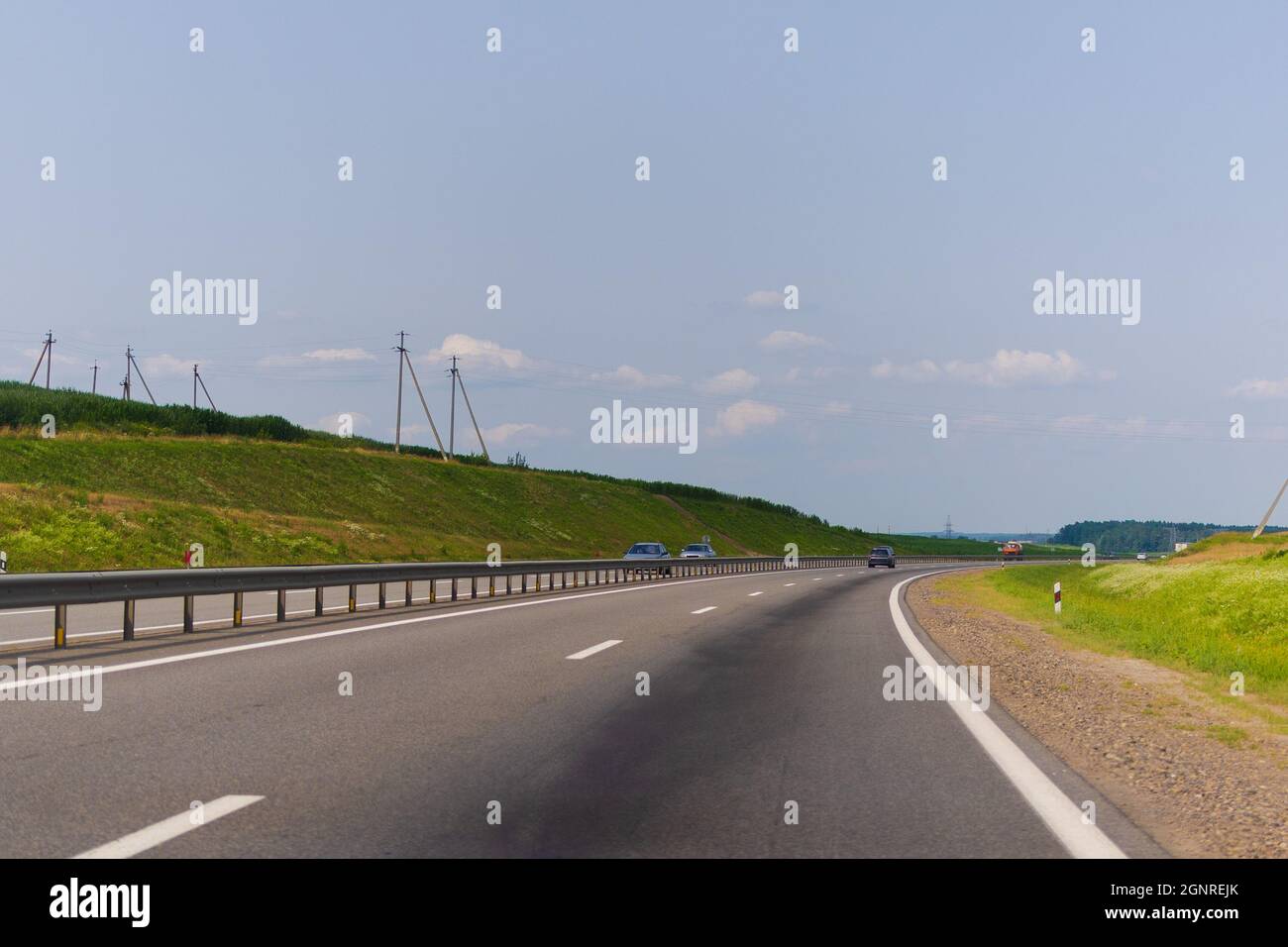 highway road in the countryside, roadside and asphalt, green forest and blue sky on a sunny day ...