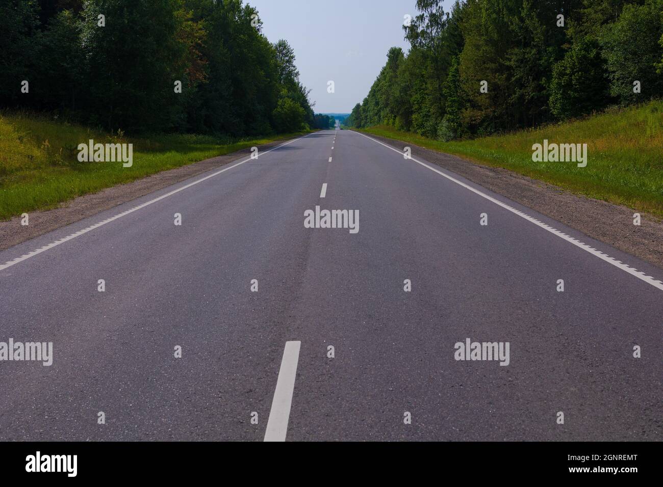 highway road in the countryside, roadside and asphalt, green forest and blue sky on a sunny day ...