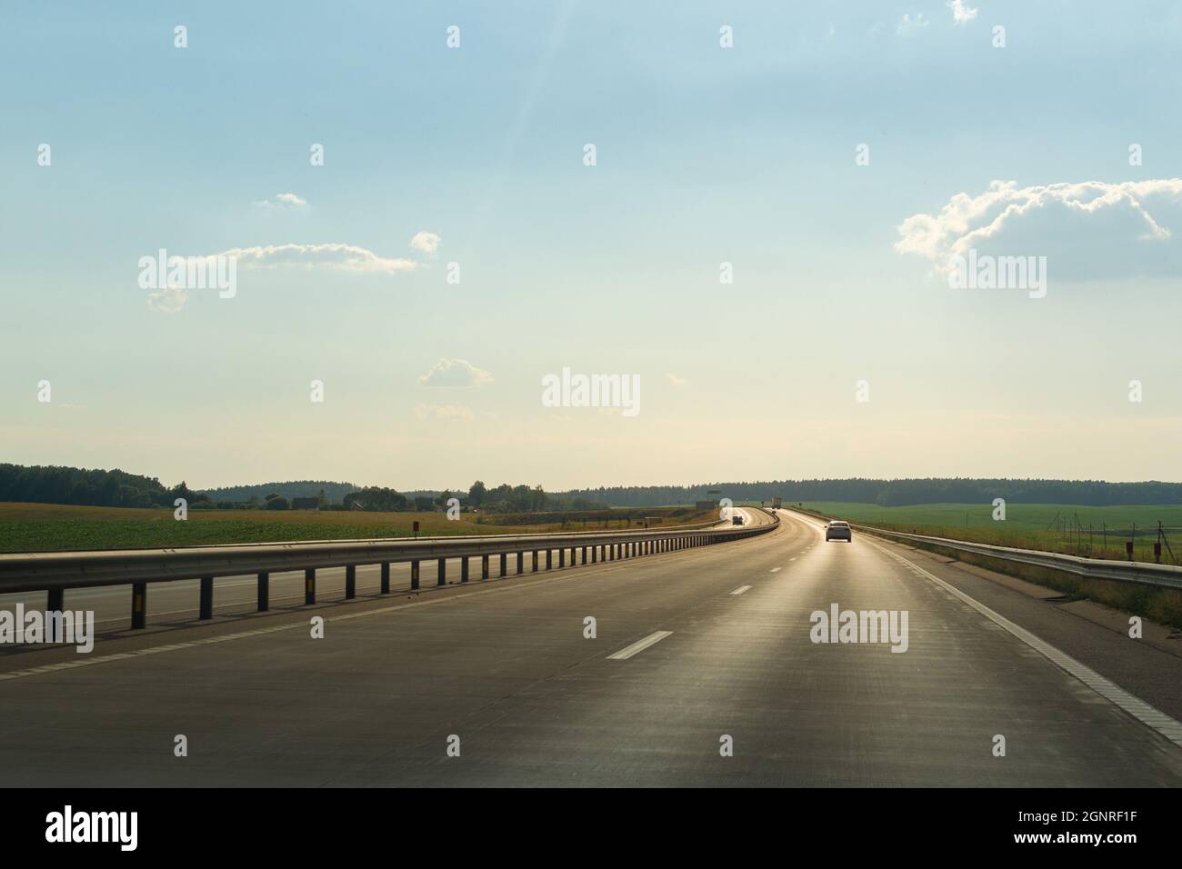 highway road in the countryside, roadside and asphalt, green forest and blue sky on a sunny day ...