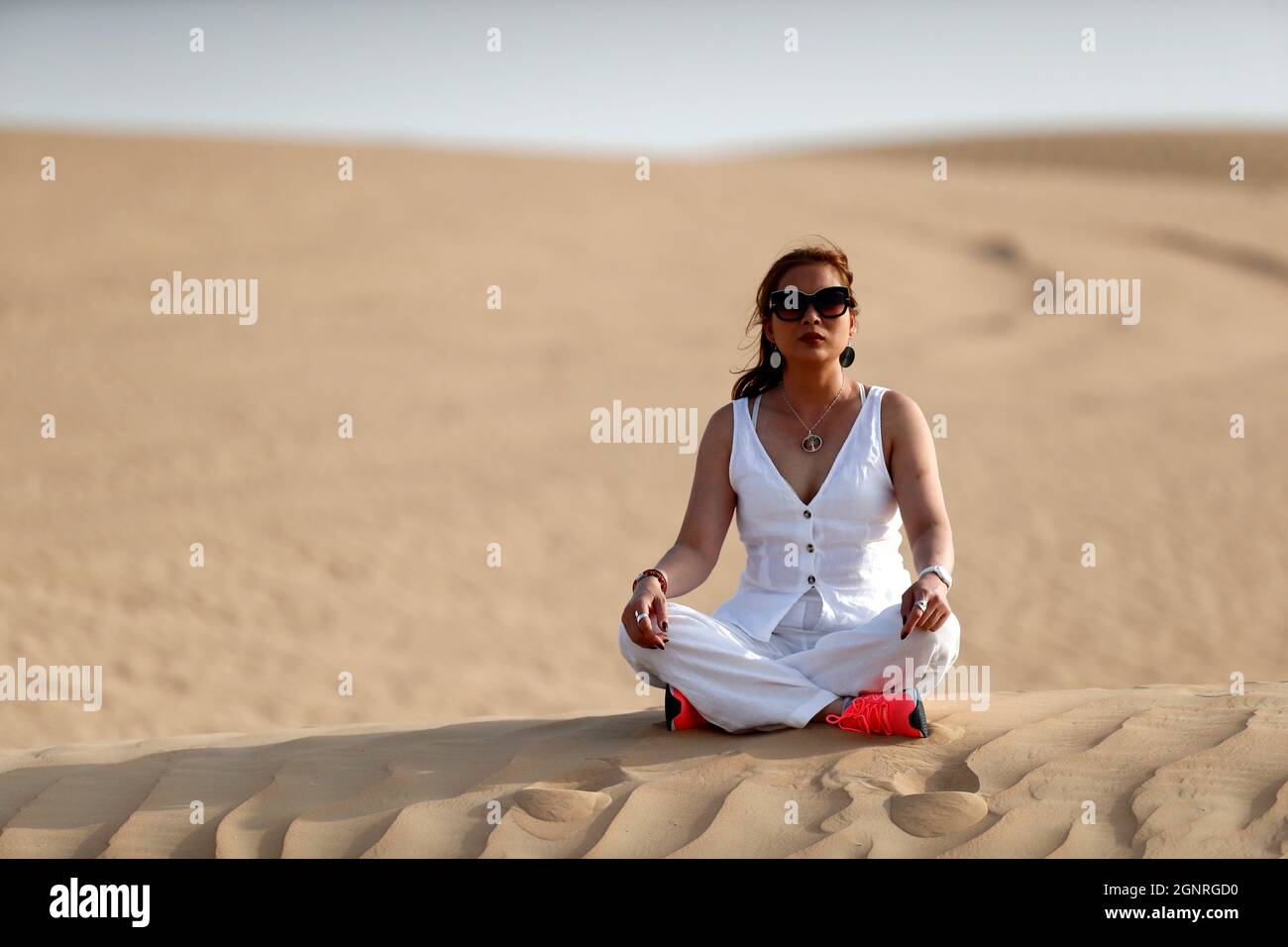 Woman meditating in Lotus Pose in desert. Dubai. United Arab Emirates ...