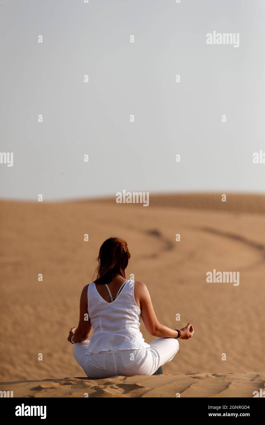 Woman meditating in Lotus Pose in desert. Dubai. United Arab Emirates ...