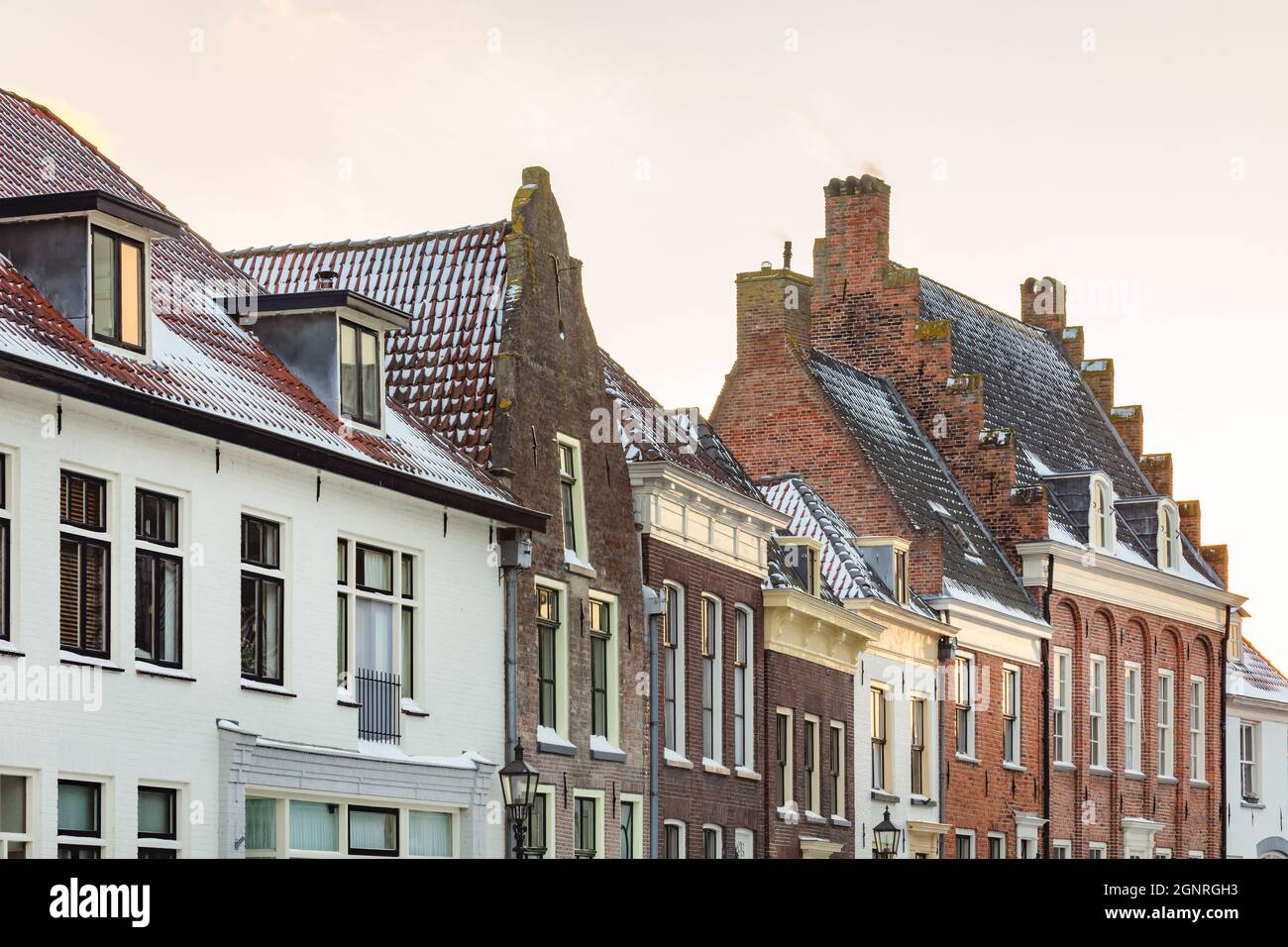 Sunset winter view of snow covered historic houses in the Dutch city ...