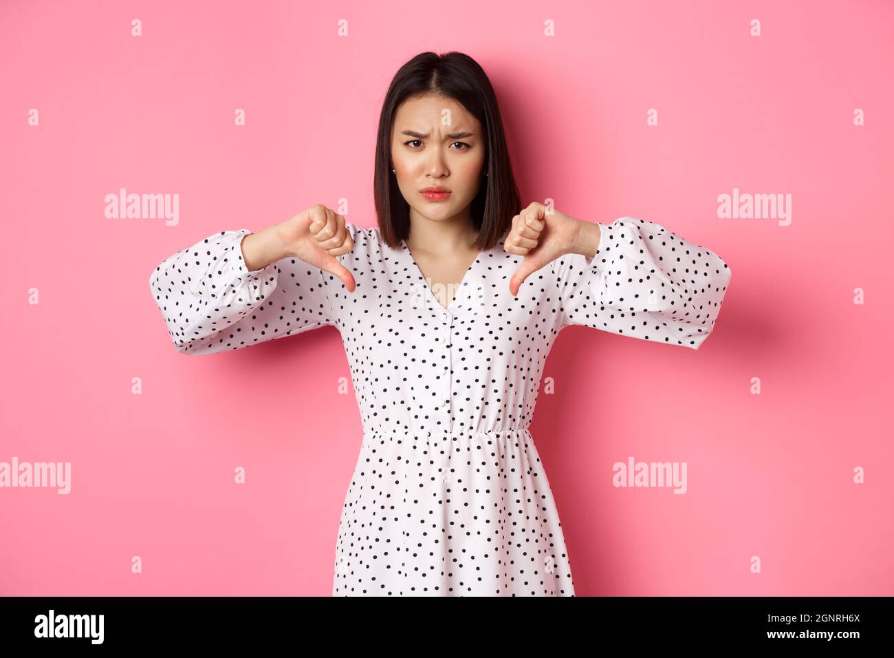 Disappointed asian woman showing thumbs-down, disapprove and dislike ...