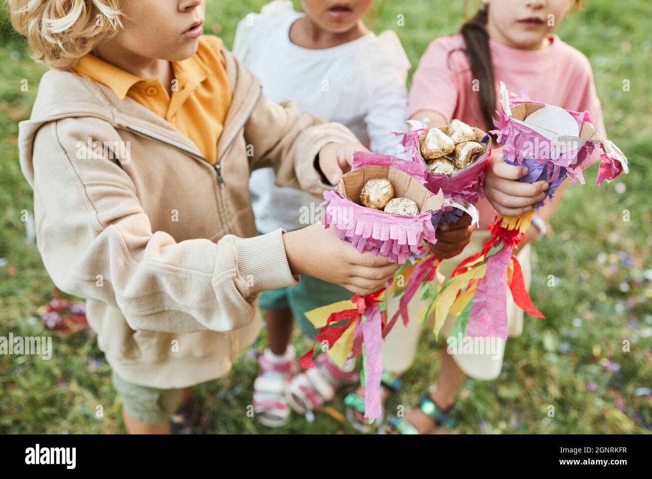 Close up children holding sweets from pinata during Birthday party ...